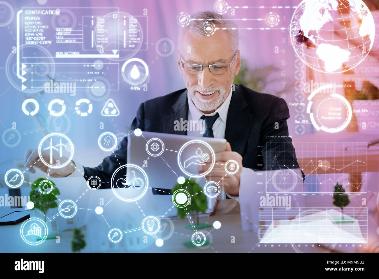 Positive professional engineer smiling and moving miniature trees while ...