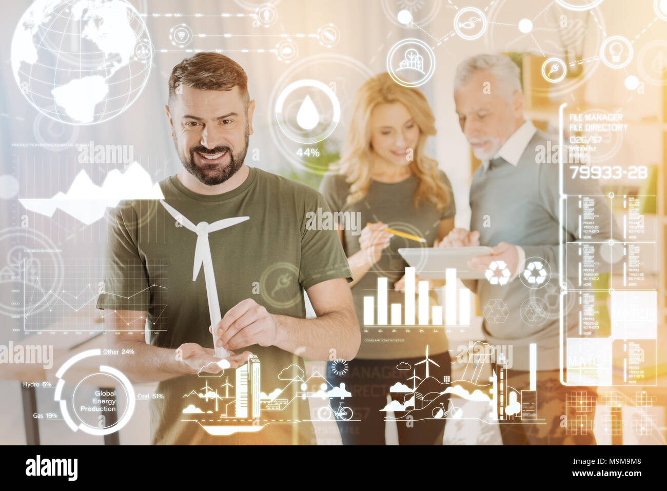 Excited young engineer smiling and showing a miniature windmill turbine ...