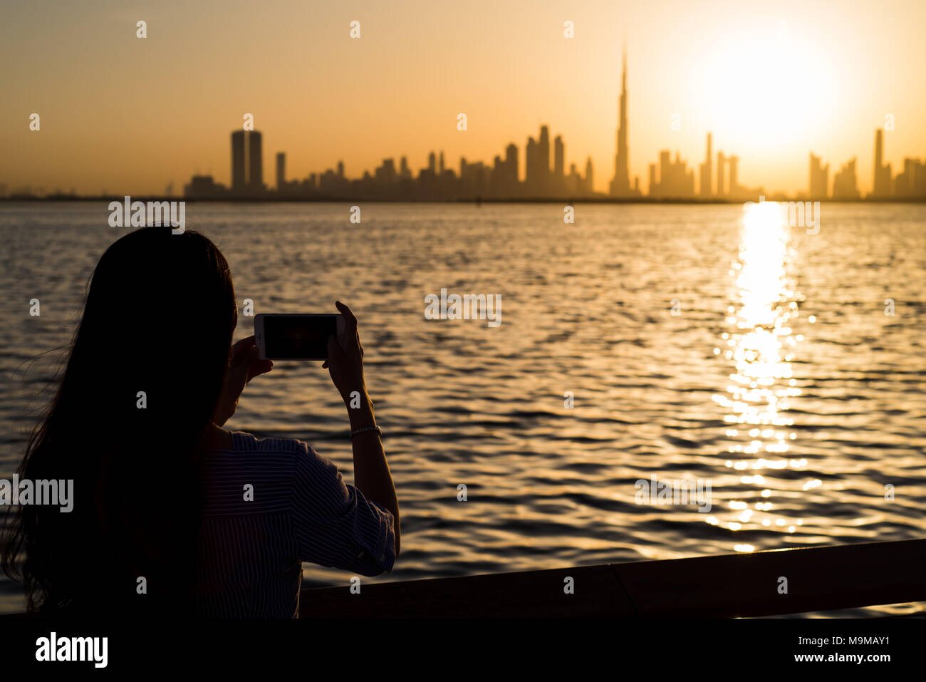 Woman taking photo of Dubai panorama at sunset Stock Photo - Alamy