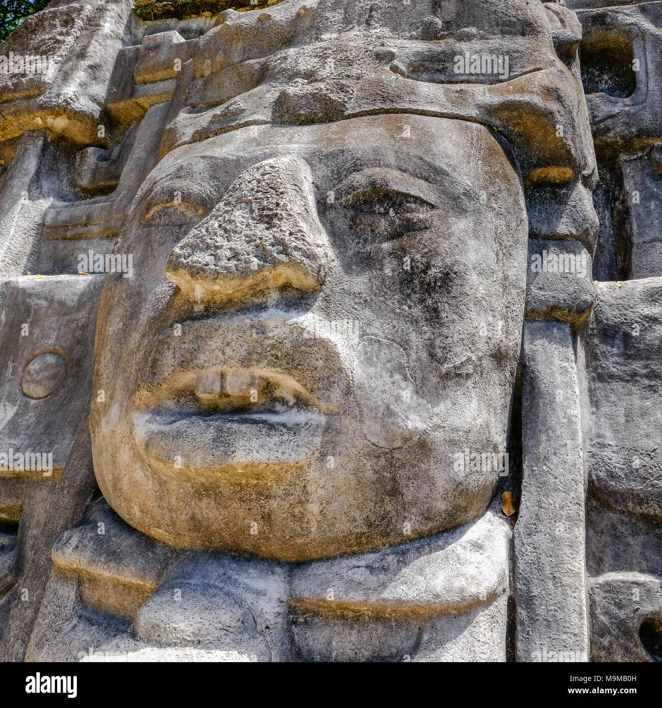 Ancient Mayan carved stone mask of a god at the ruins of Lamanai ...