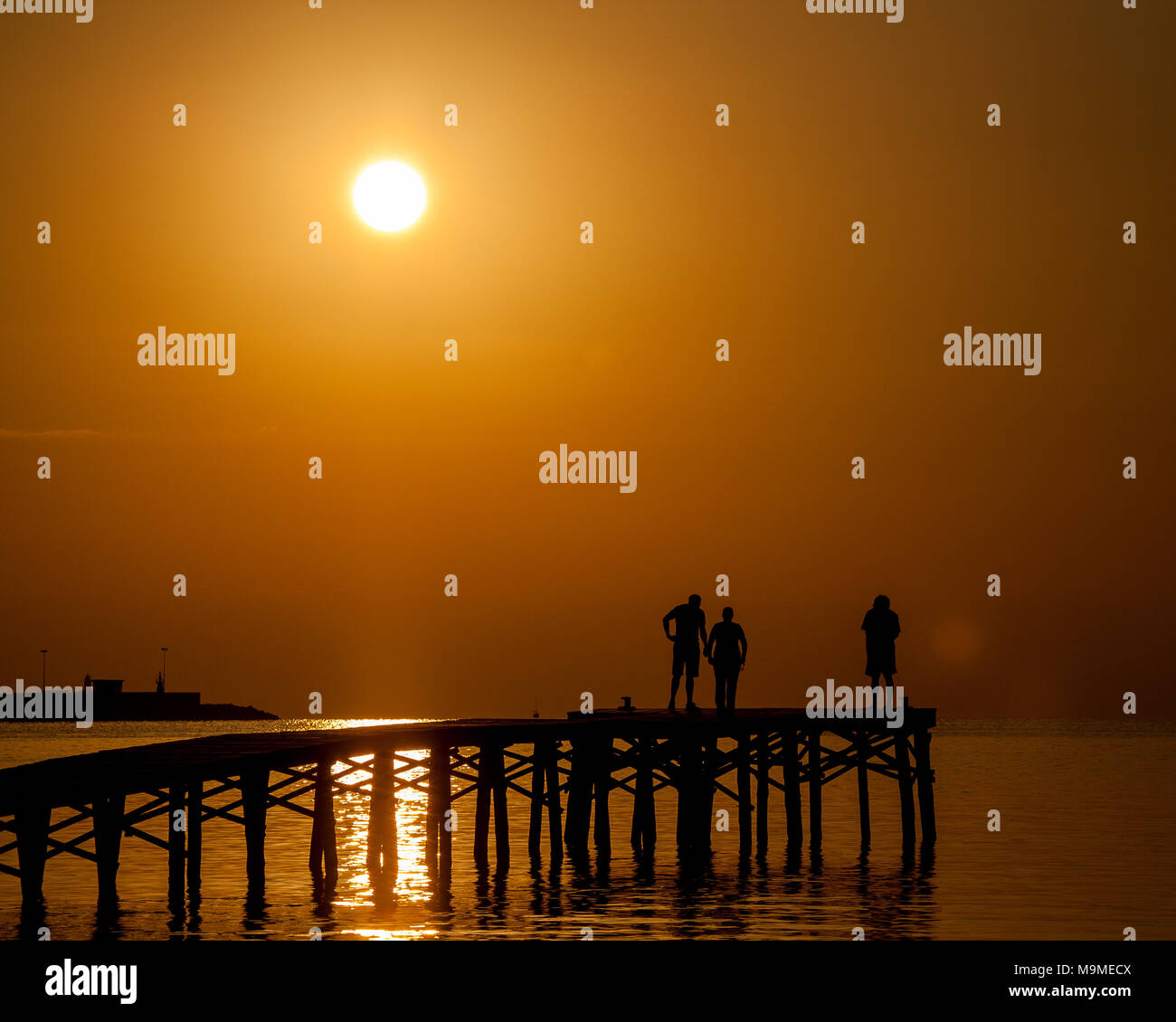 Silhouette of a family on a jetty at sunrise in Alcudia, Mallorca Stock ...