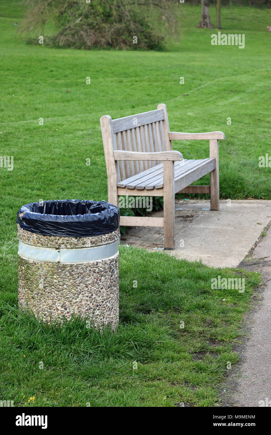 Wooden park seat on a concrete plinth with an adjacent concrete litter ...
