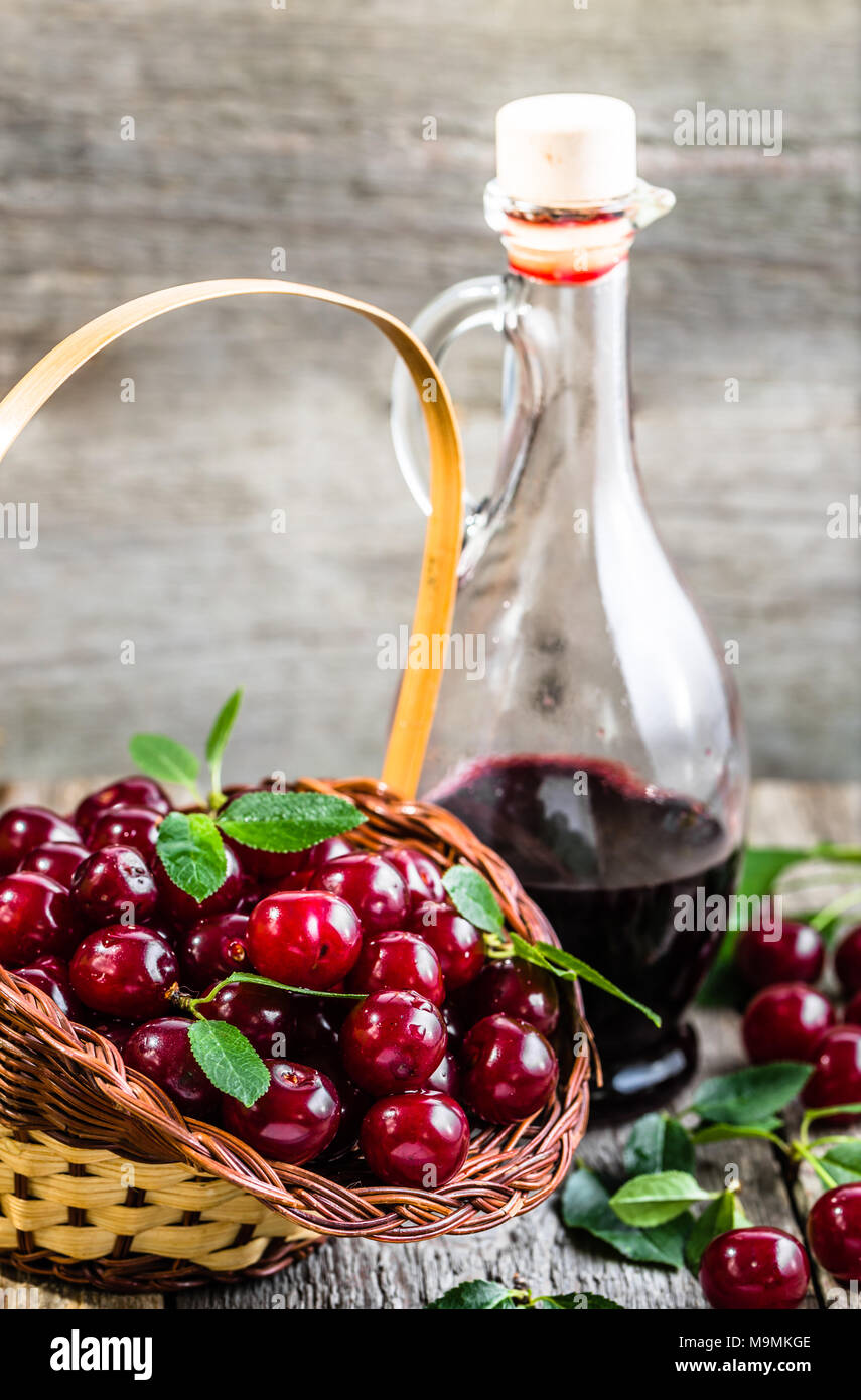 Cherry wine in a glass bottle on wooden table. Sweet alcohol made from ...