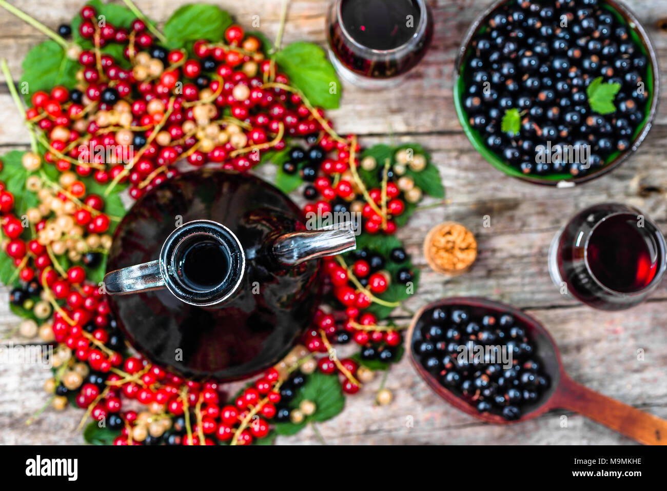 Fruit liquor in a bottle and glass of sweet alcohol on wooden table ...