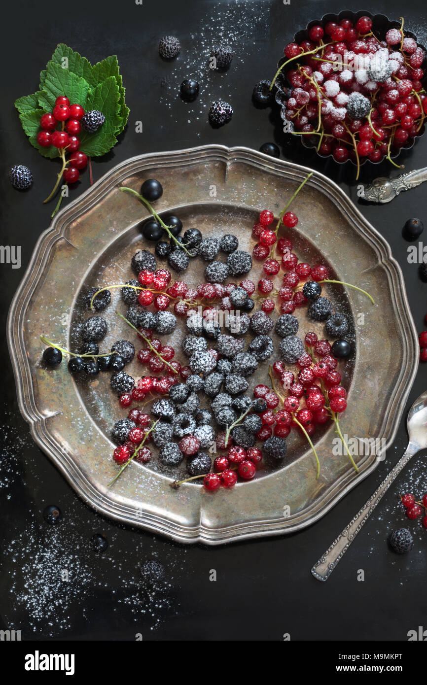 Fresh red and black currant, black raspberries garnish sugar powder ...