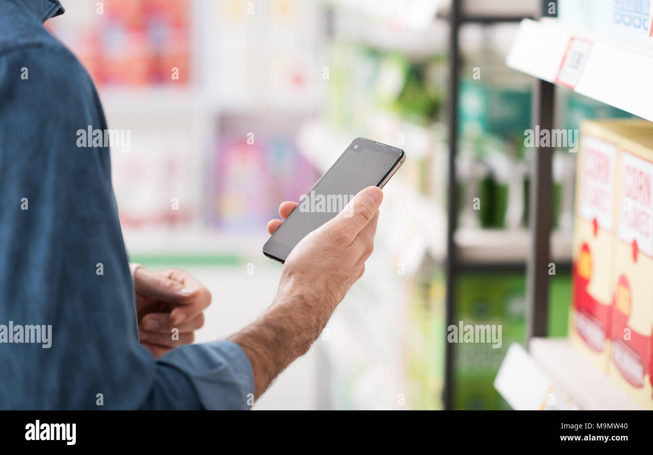 Man shopping at the supermarket, he is searching products on the shelf ...