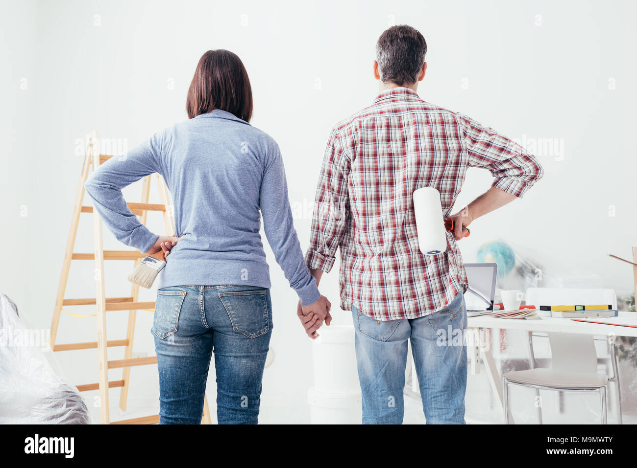 Loving couple staring at their freshly painted room, back view: home ...