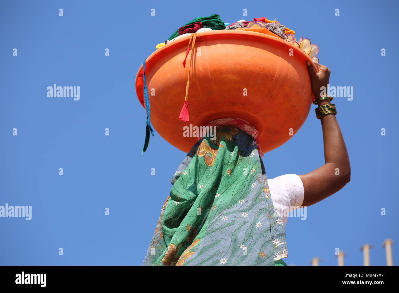Indian woman after washing clothes with wash bowl on her head ...