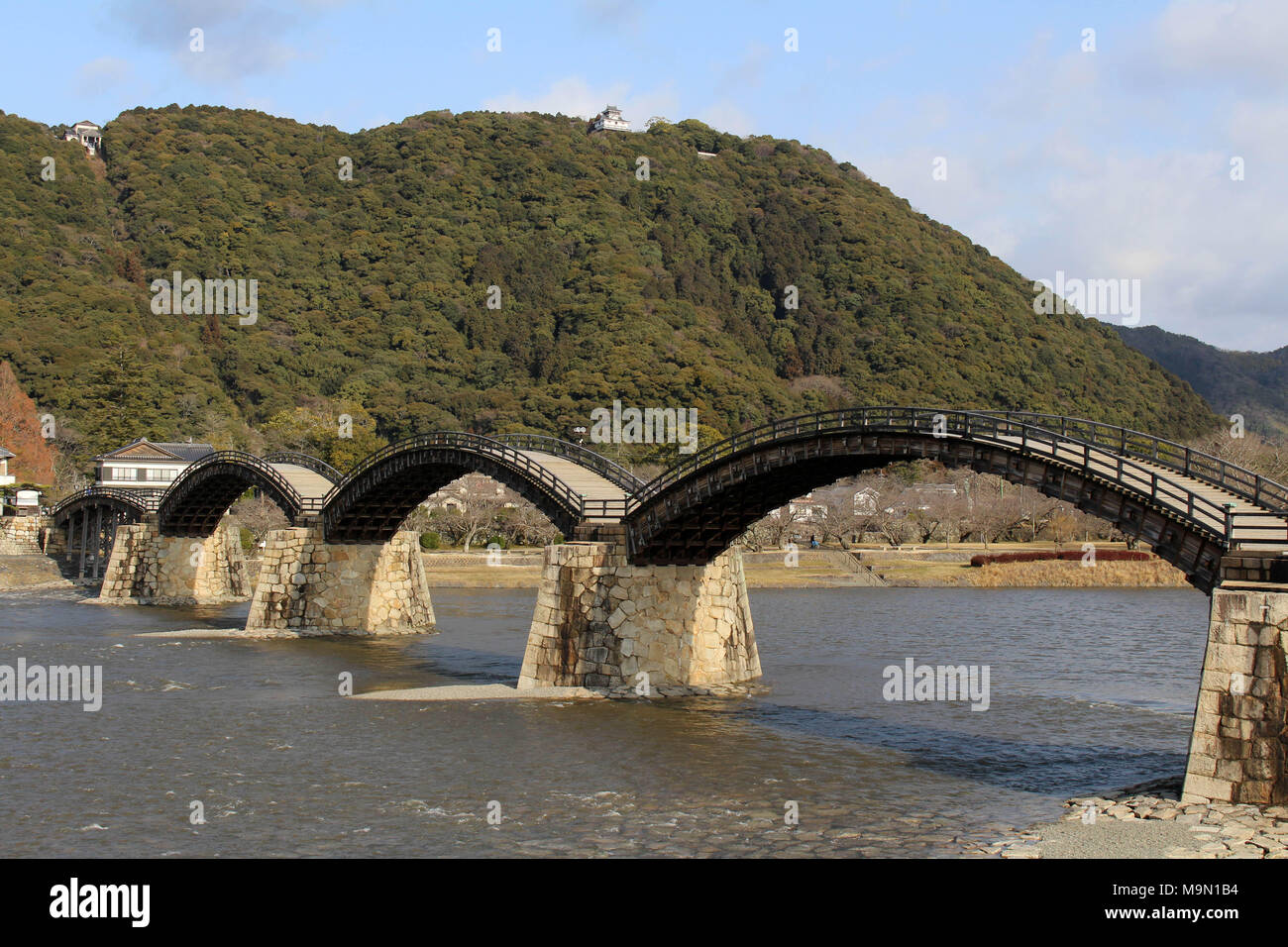 The iconic Kintai Bridge made of wood. On top of the hill is the ...