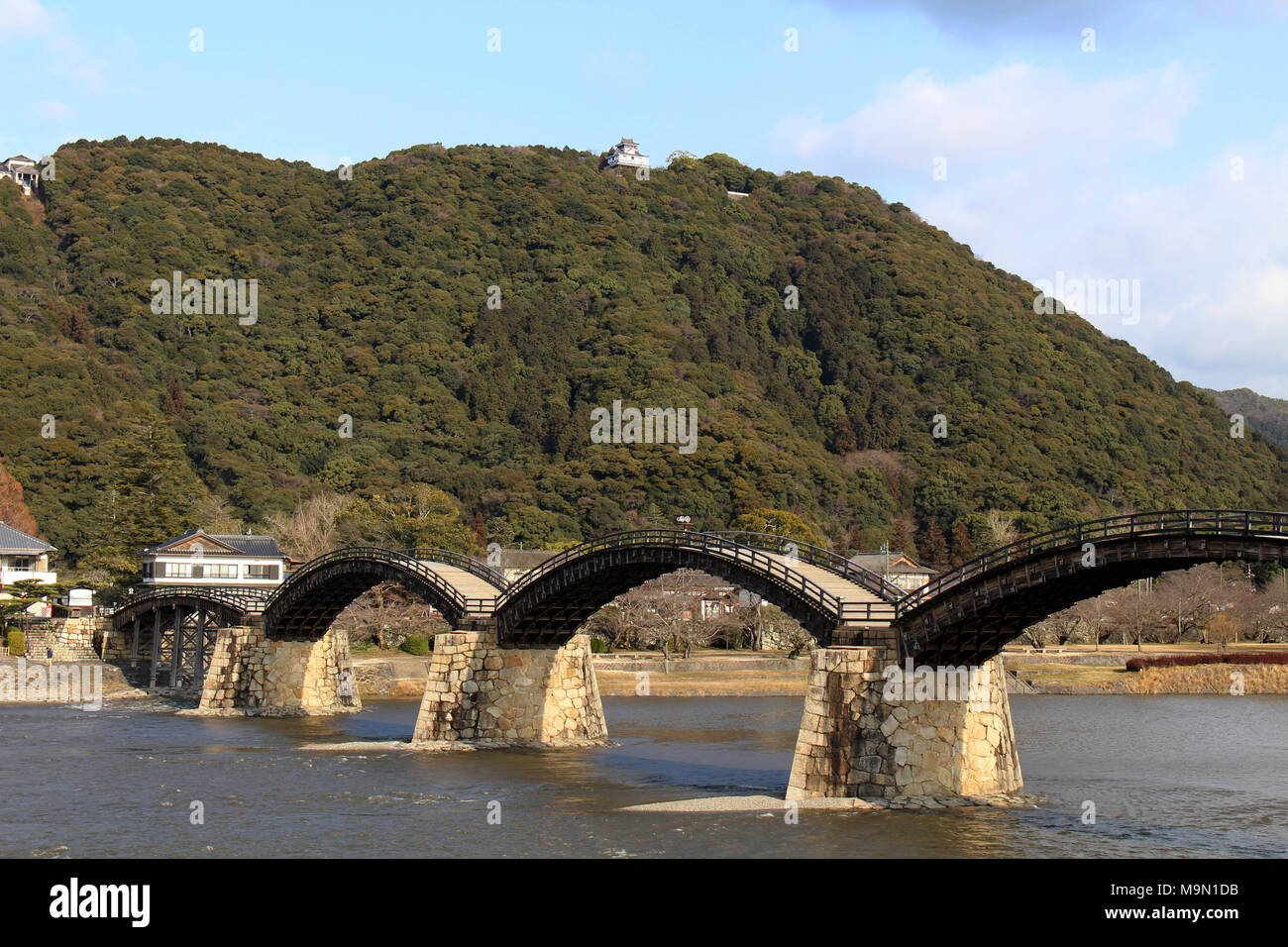 The iconic Kintai Bridge made of wood. On top of the hill is the ...