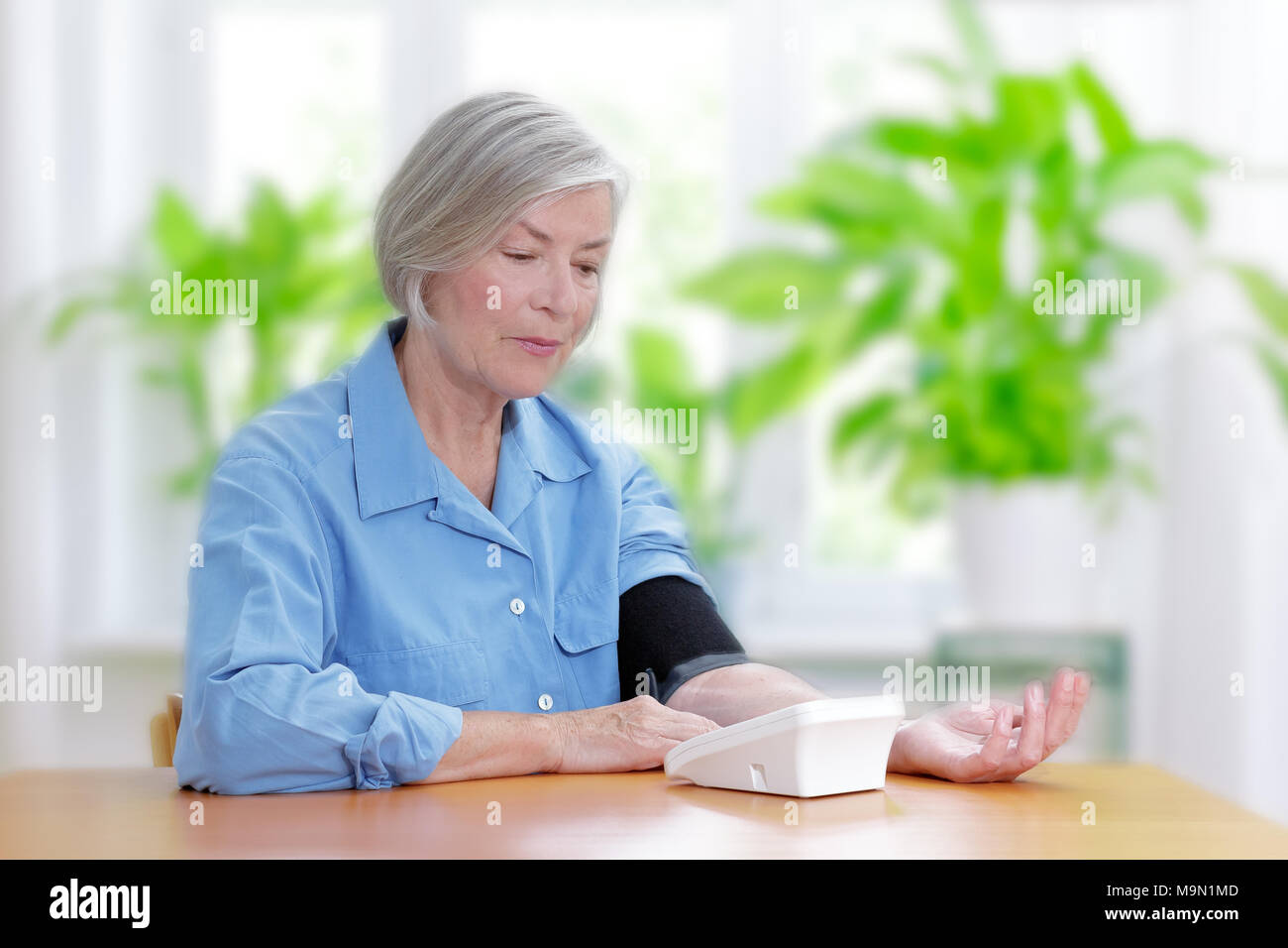 Senior woman suffering from hypertension sitting at a table in her ...