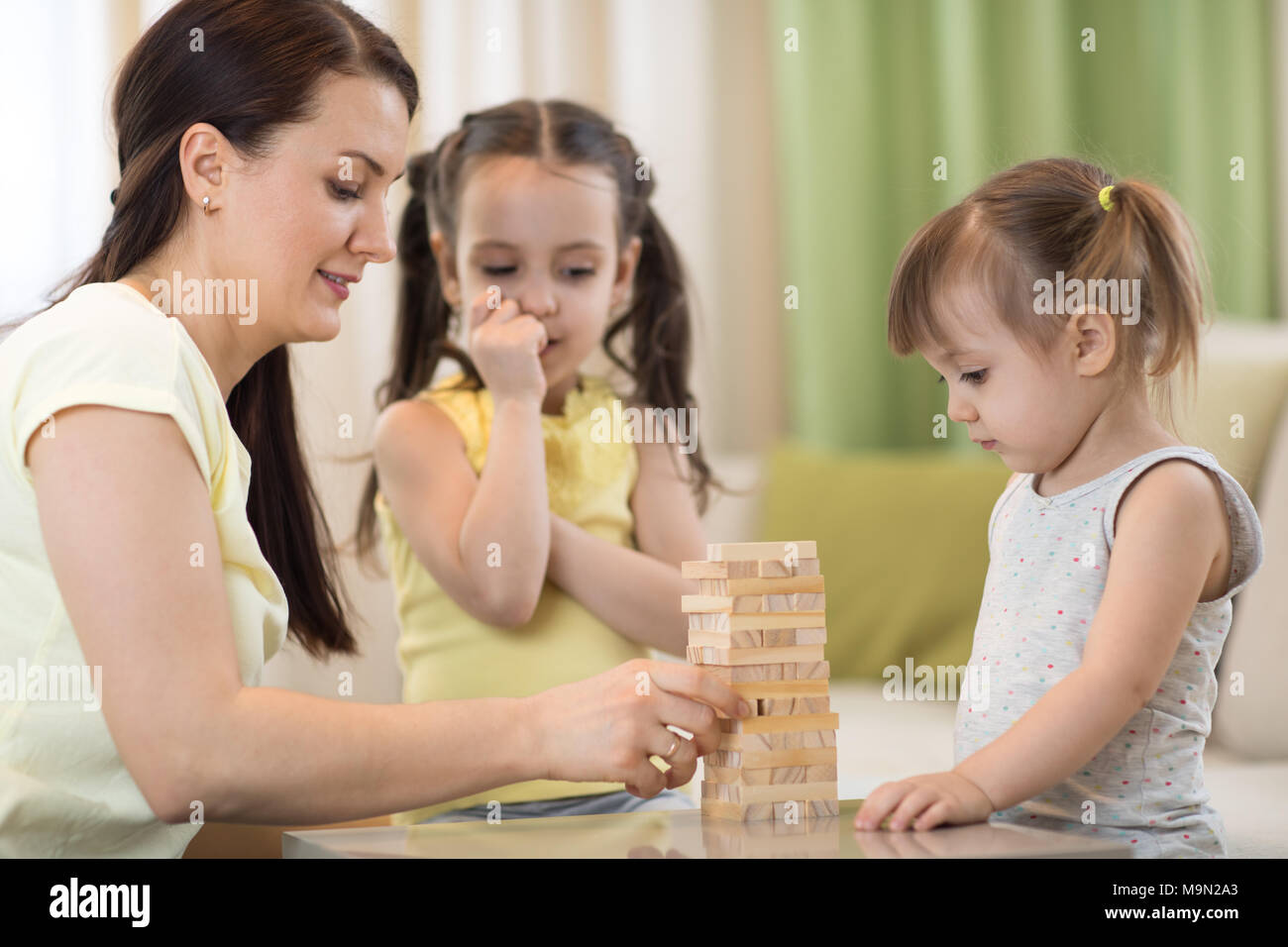 Happy mom and daughters at the table playing board game Stock Photo - Alamy