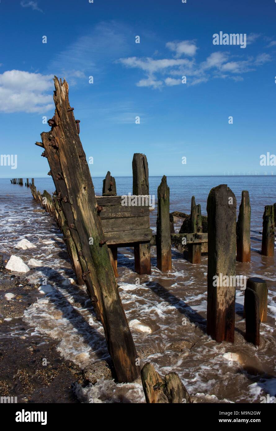 Wood in the sea water in Yorkshire with blue sky and little cloud ...