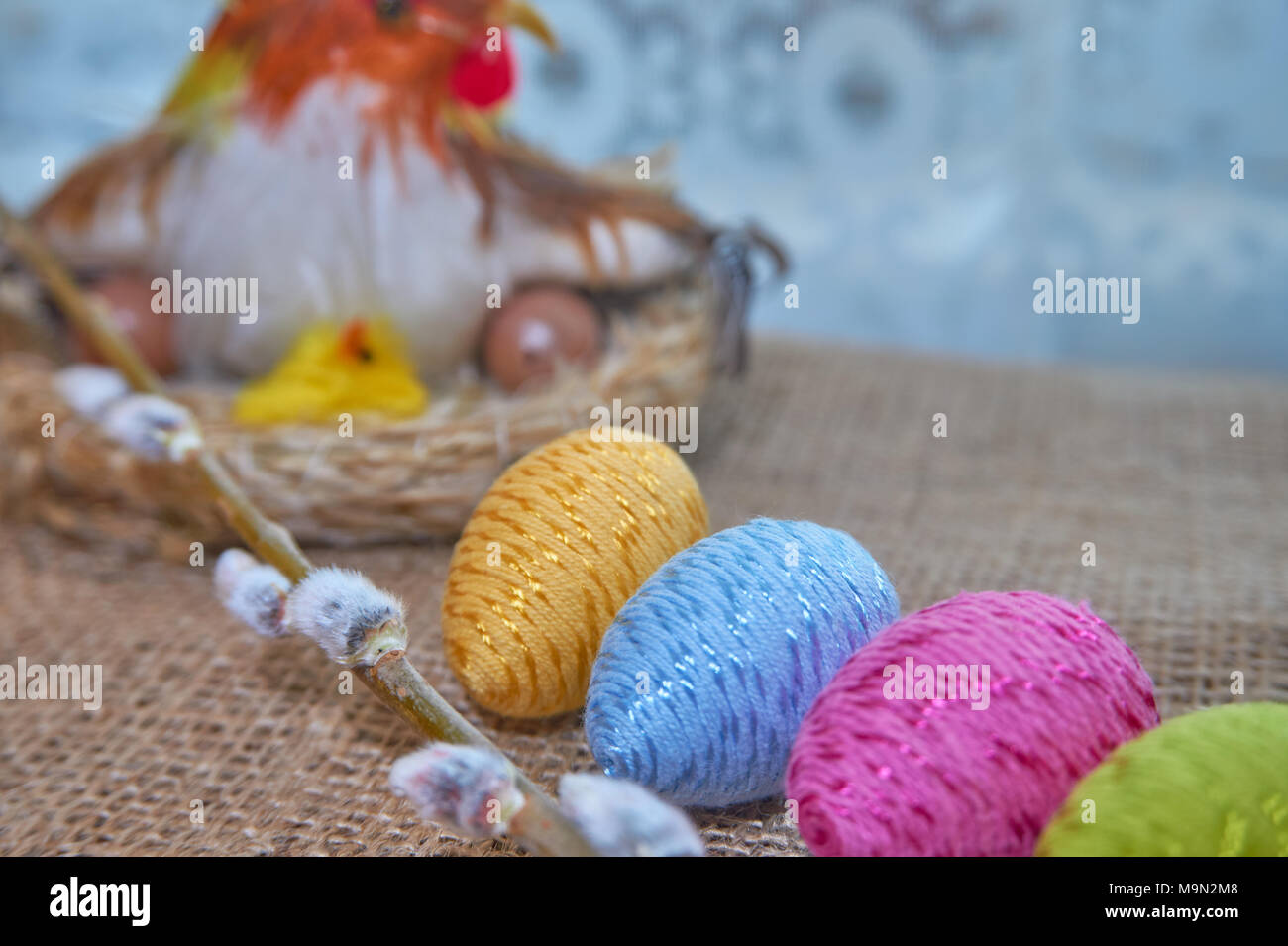 Colorful easter eggs and willow branch on natural jute fabric ...