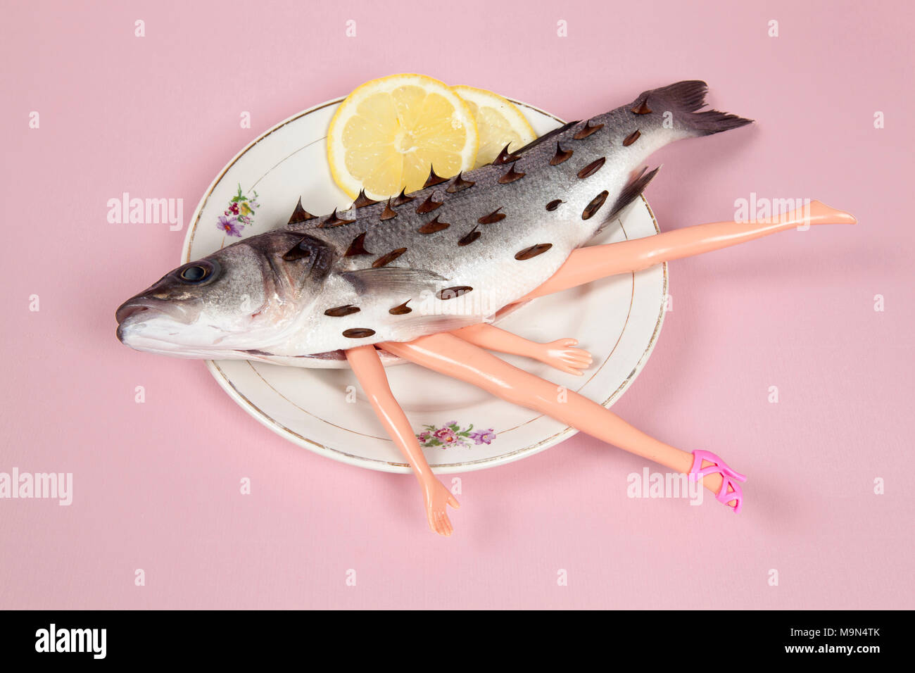 A bass fish with arms and legs of a doll inside on a flower plate ...