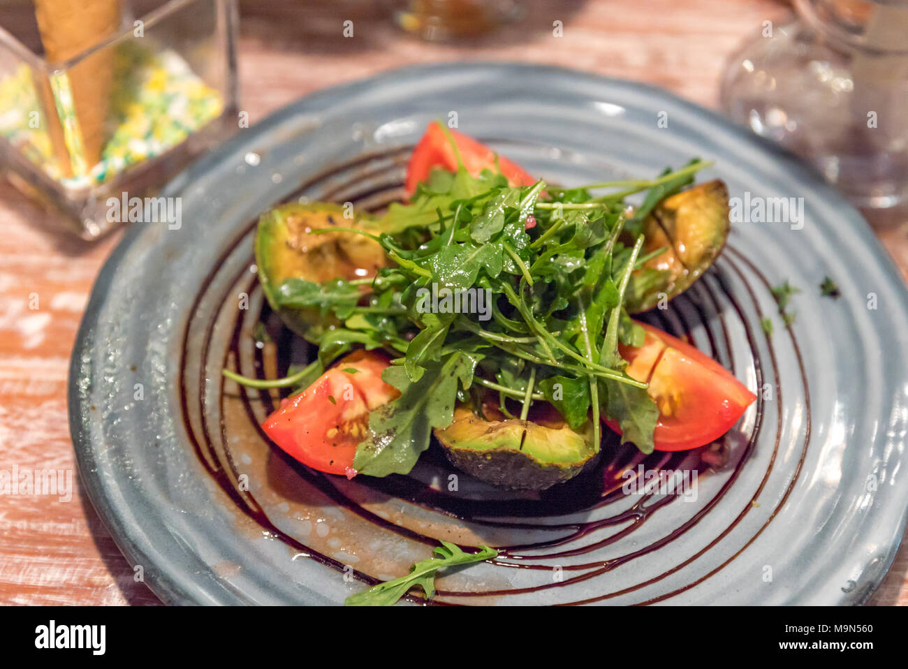 Grilled avocado salad with tomato and rocket Stock Photo - Alamy