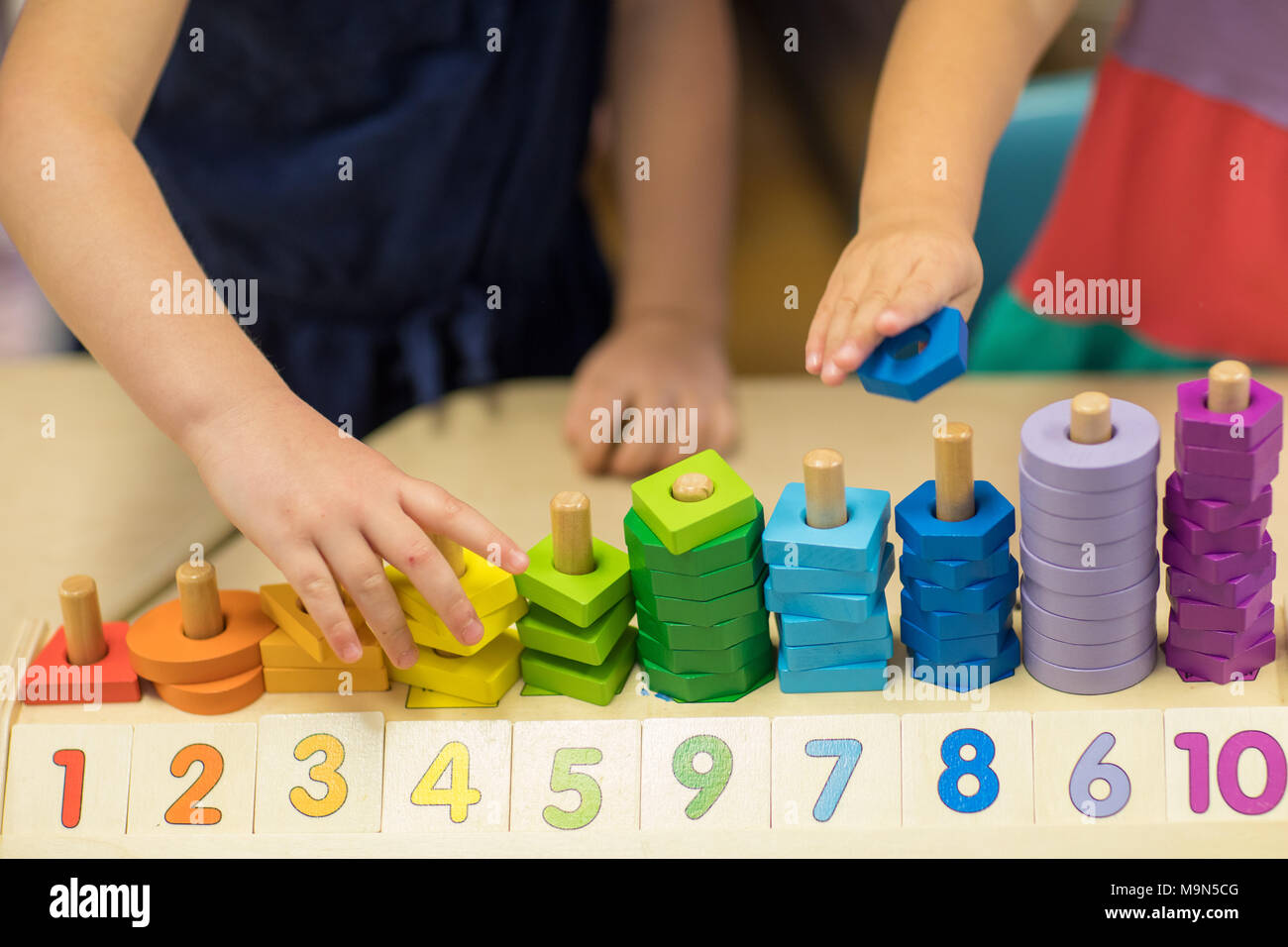 children stacking colorful wooden shapes Stock Photo - Alamy