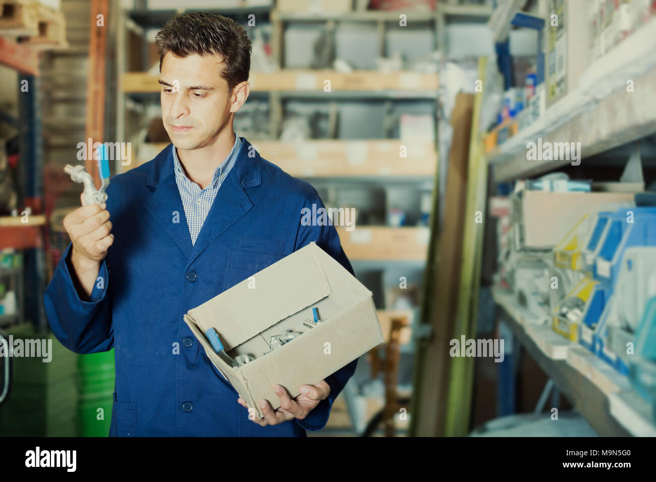 foreman is choosing small details which is in boxes near shelving in ...