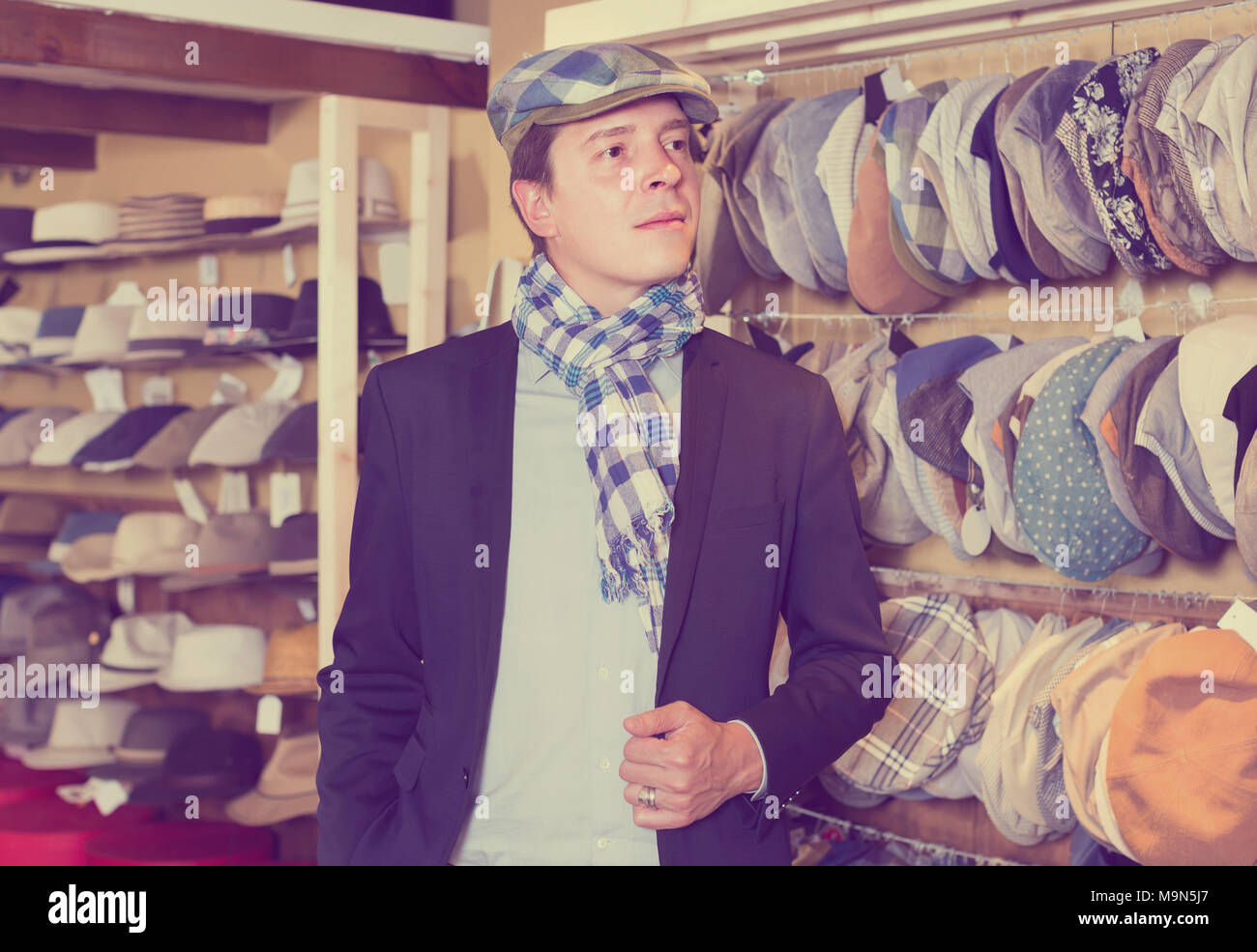 portrait of positive spanish young male try on newboy cap at the ...