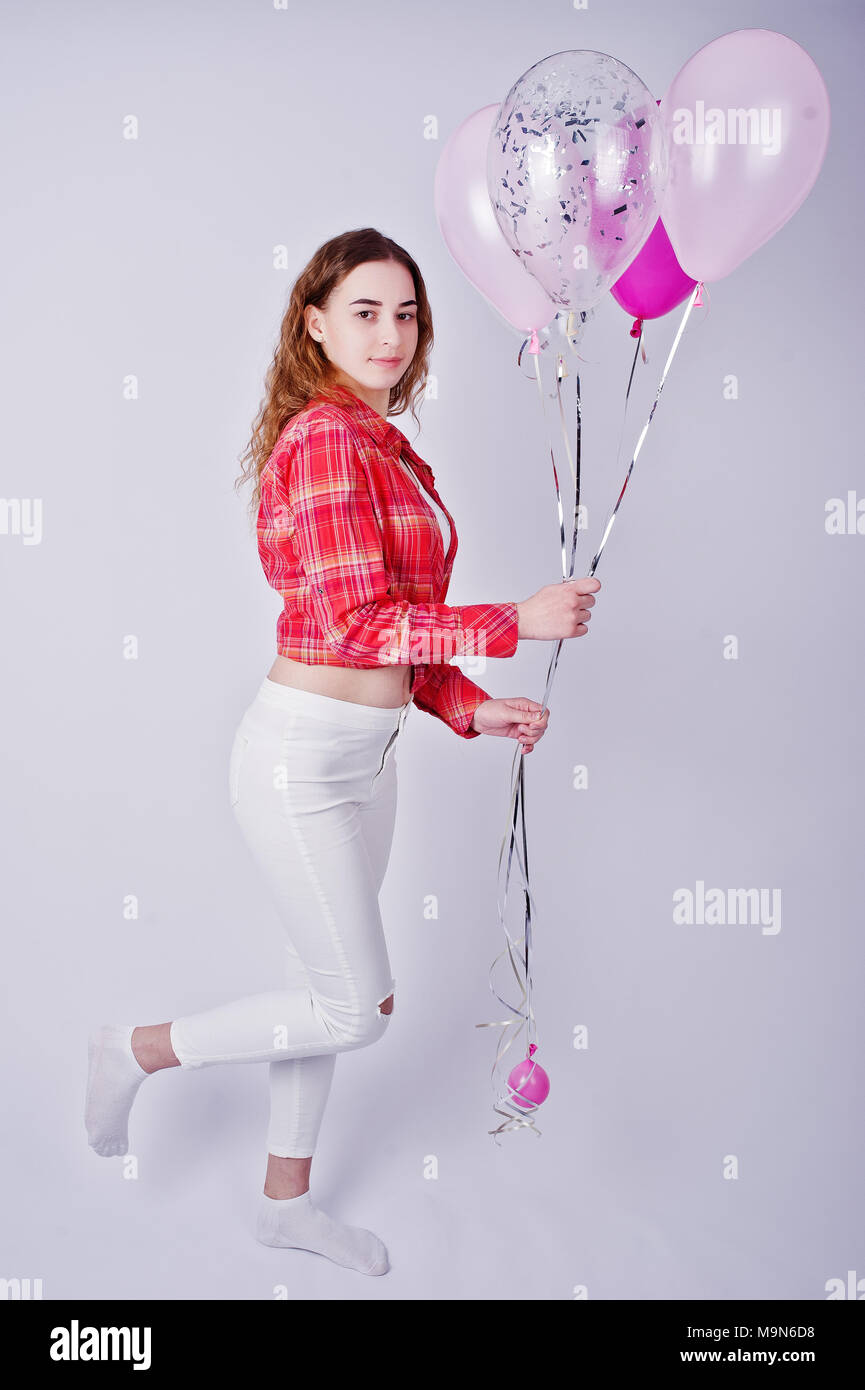 Young girl in red checked shirt and white pants with balloons against ...