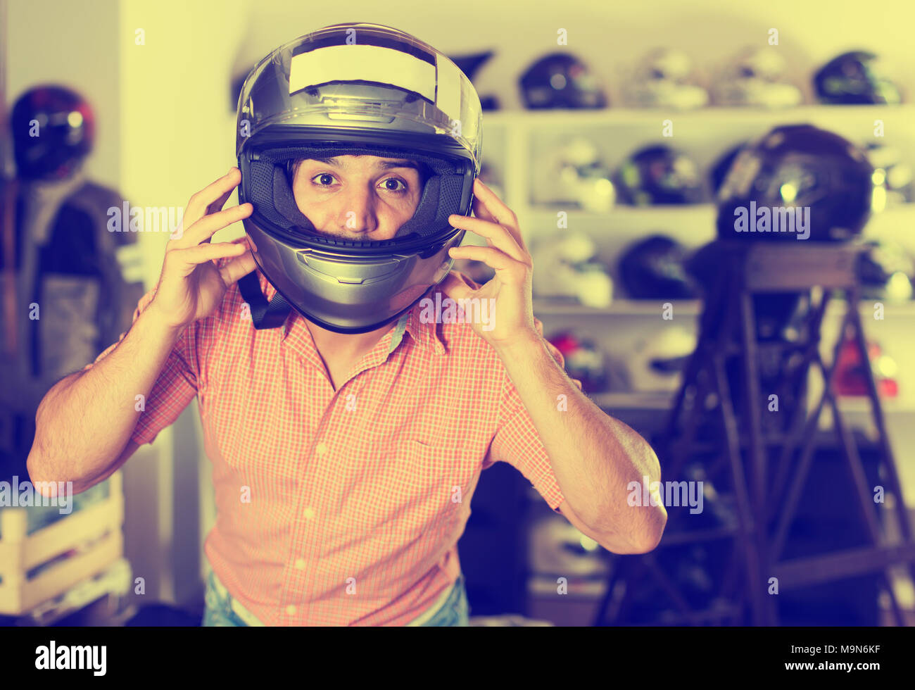 Adult man is trying up new helmet for head protection in the moto shop ...