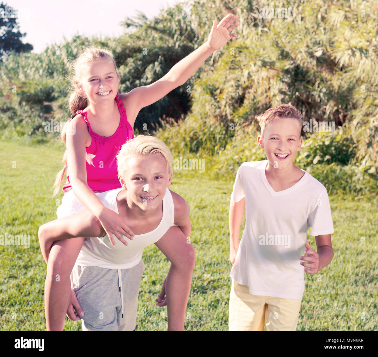 Happy children running together outdoors, boy carrying girl on back ...
