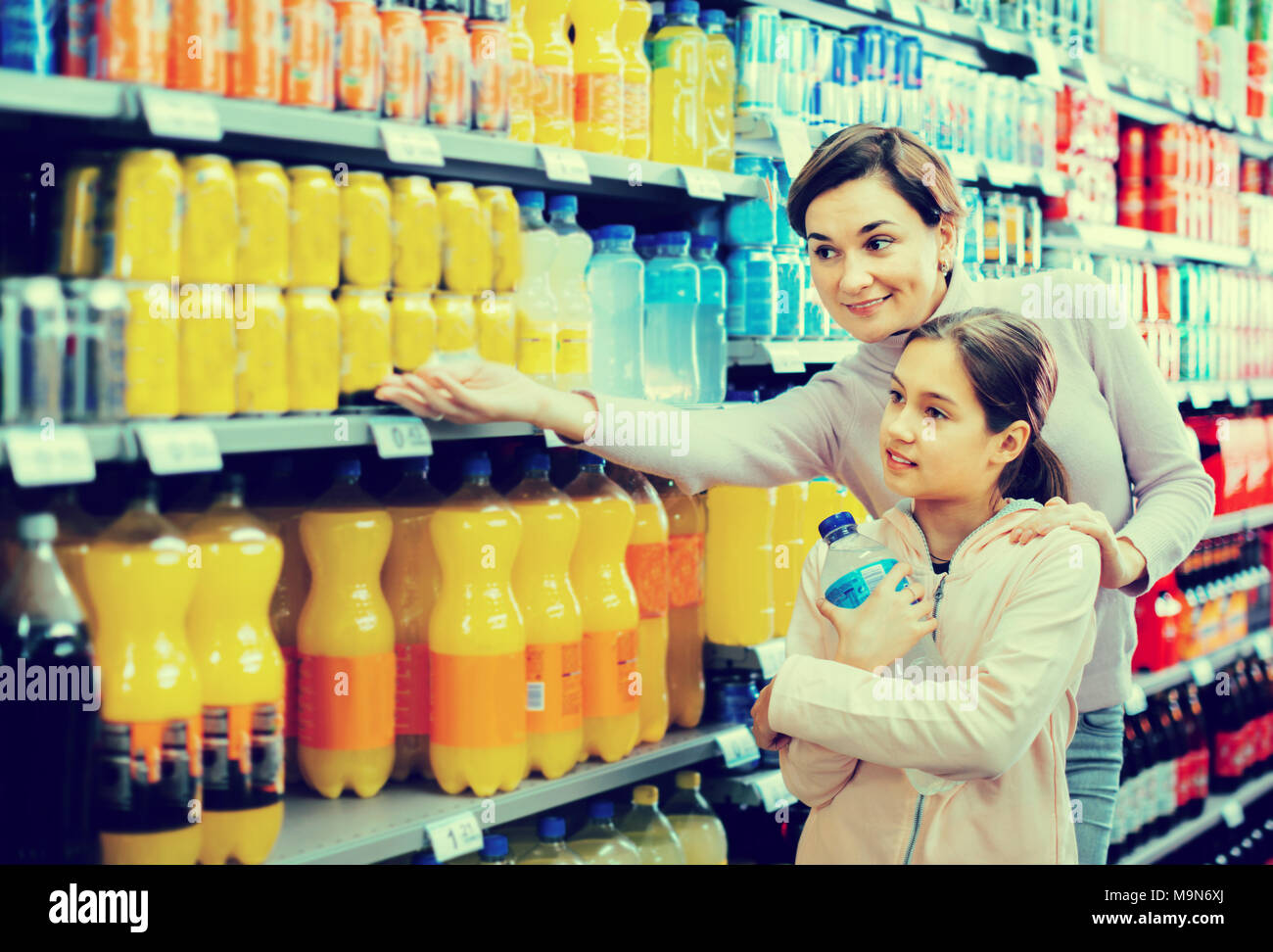 Glad positive smiling female shopper with teenage daughter searching ...