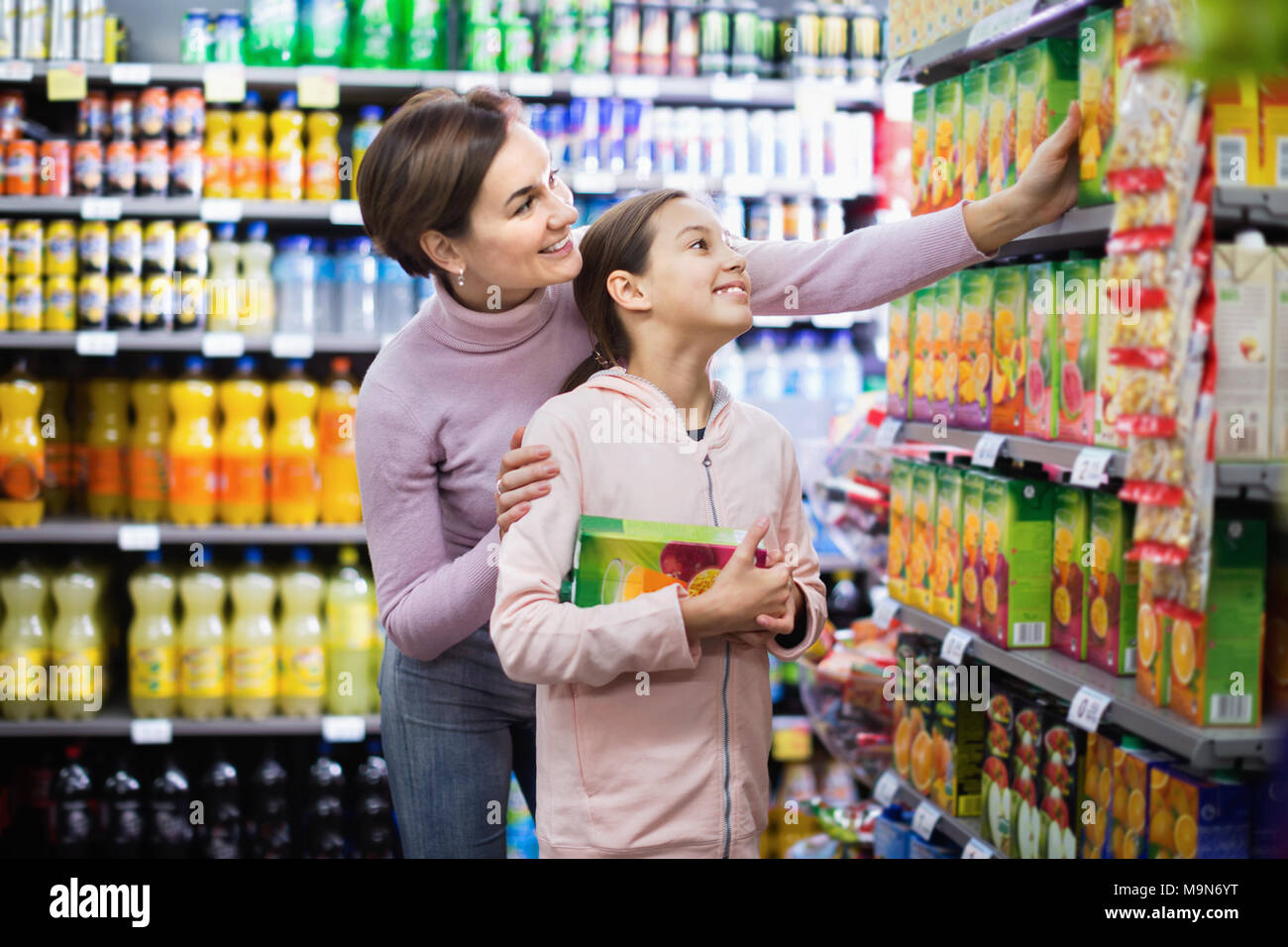 Glad female shopper with teenage daughter searching for beverages in ...