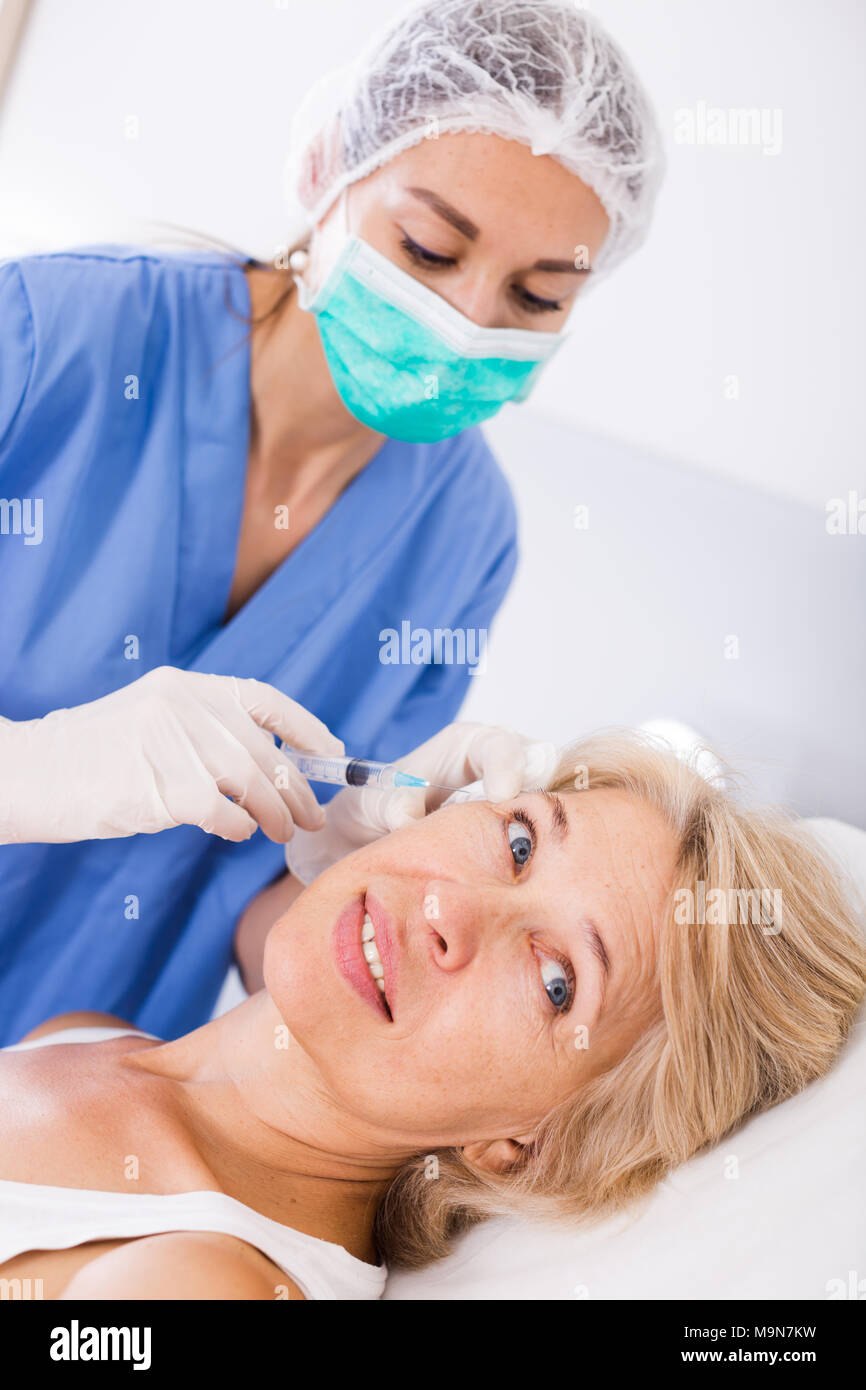 Senior woman getting injection for facial rejuvenation procedure in ...