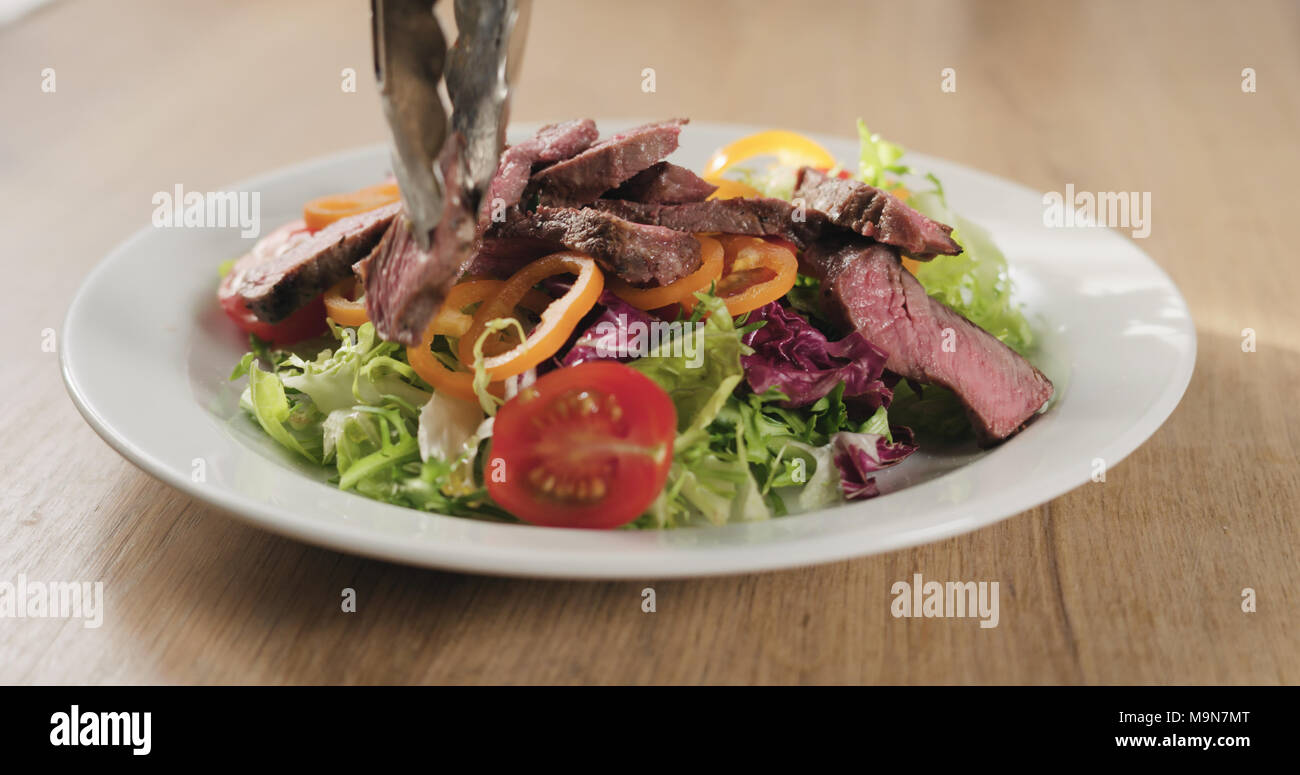 adding fillet mignon steak into salad Stock Photo - Alamy