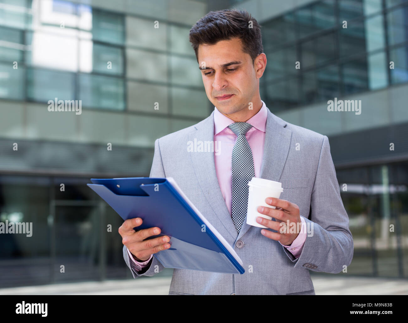 Successful serious manager of large plant reading papers outdoor Stock ...