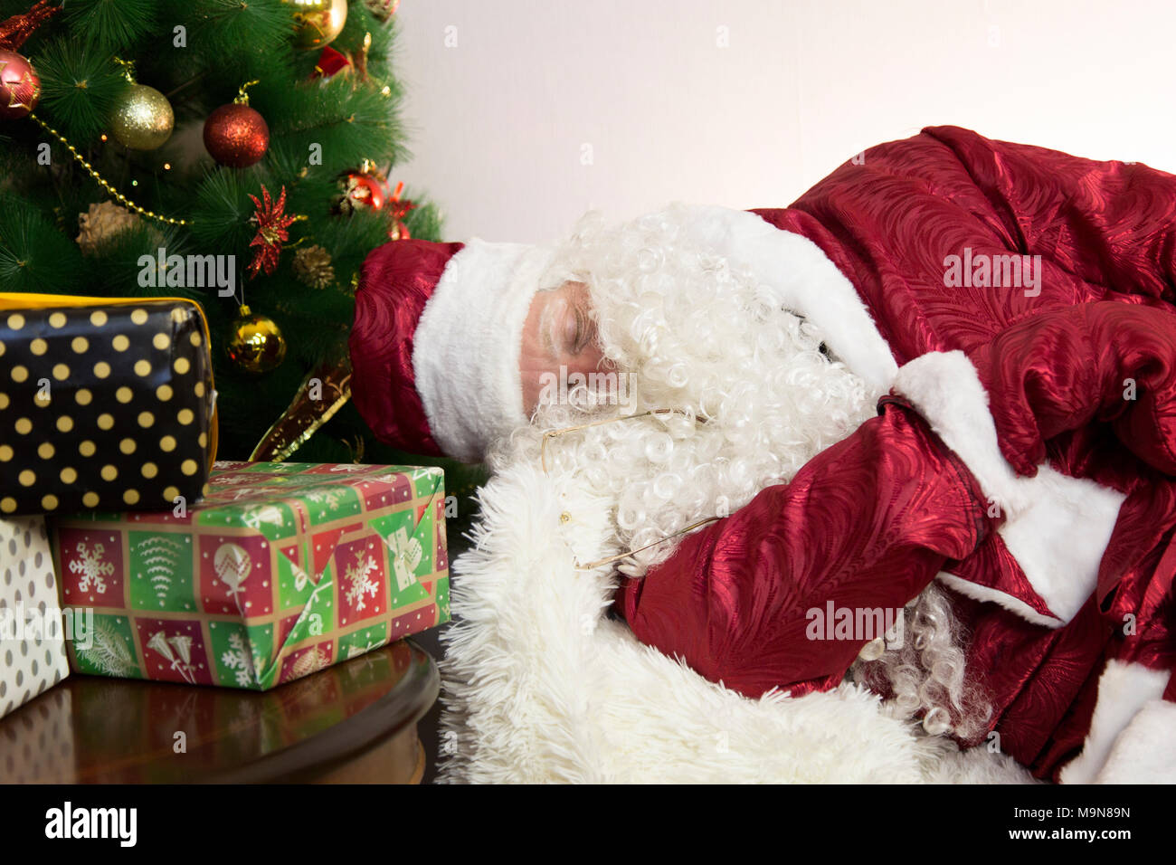 Santa Claus fell asleep on a white sofa in the room with a Christmas ...