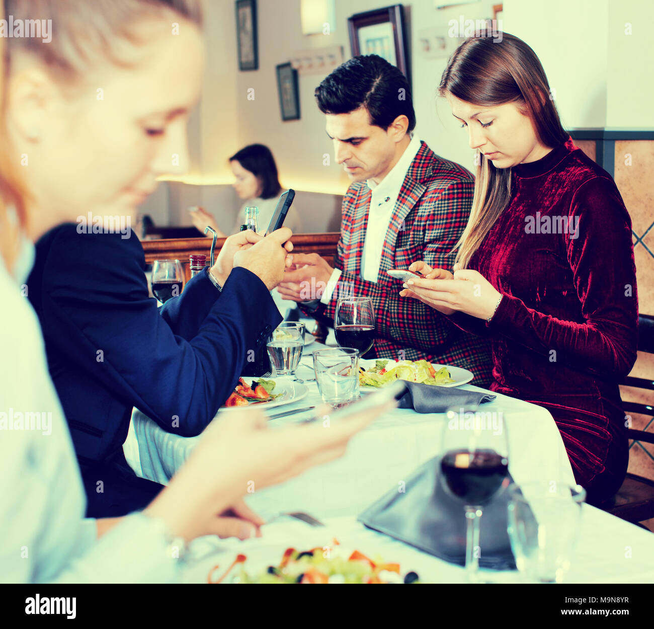Modern young cheerful positive people busying with phone during evening ...
