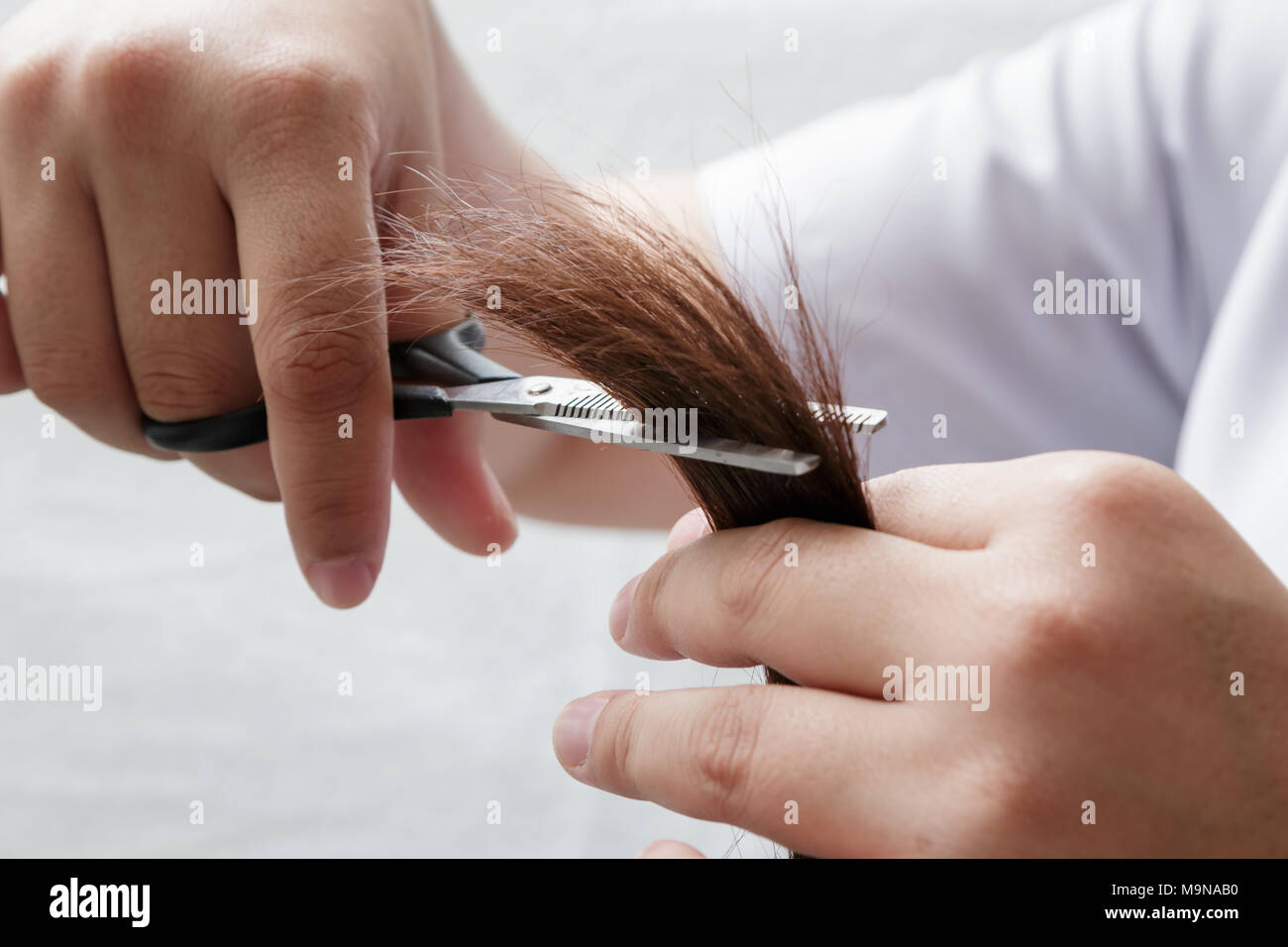 Closeup hairdresser trimming brown hair with scissors Stock Photo - Alamy