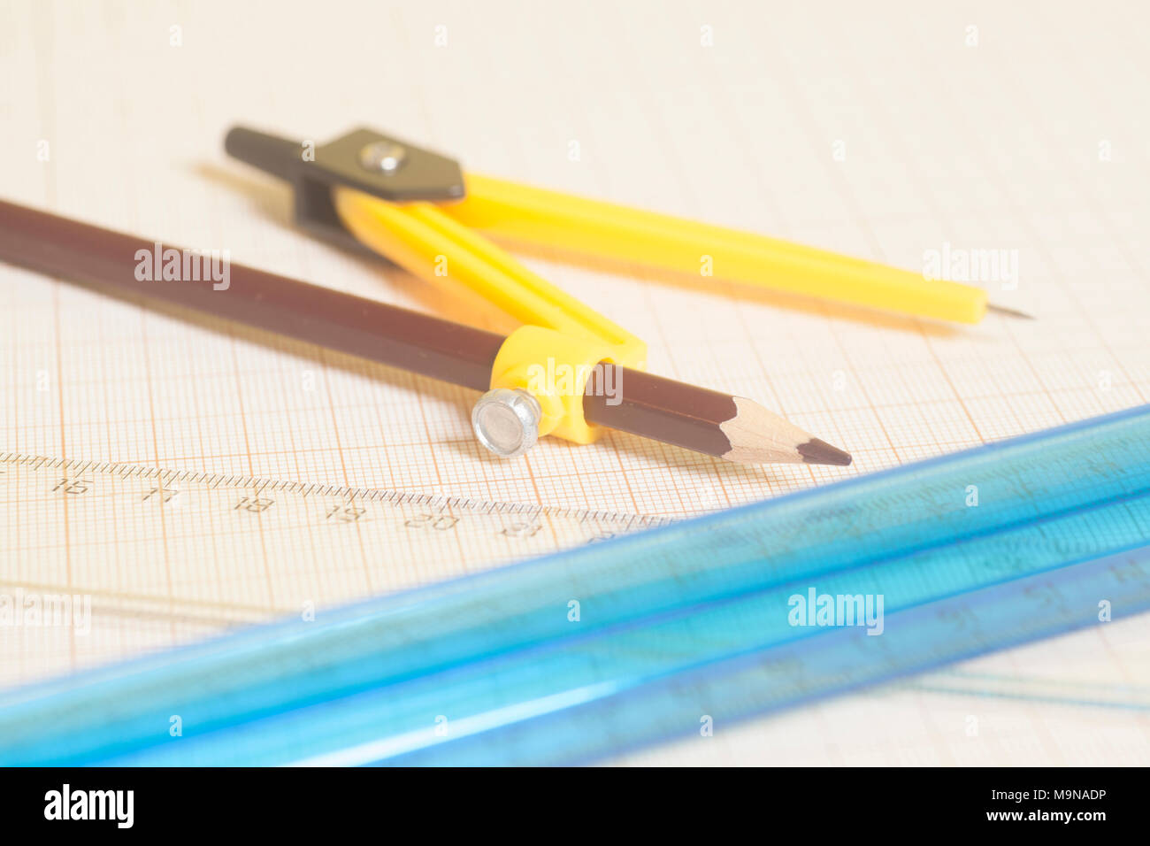 Yellow Drawing compass with black pensil and rulers on graph paper ...