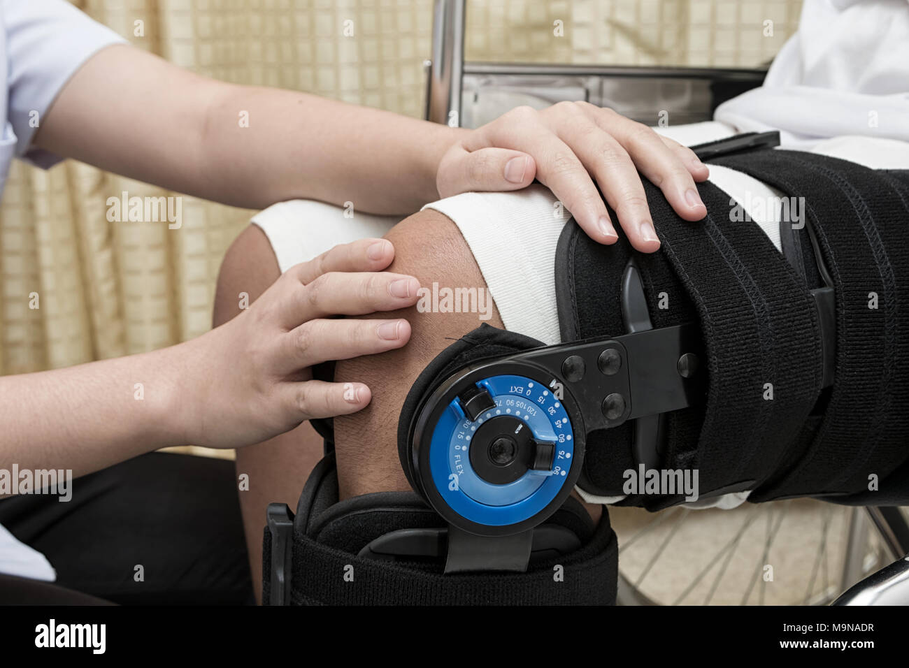 Female physiotherapy adjusting walking brace on patient's leg in wheel ...