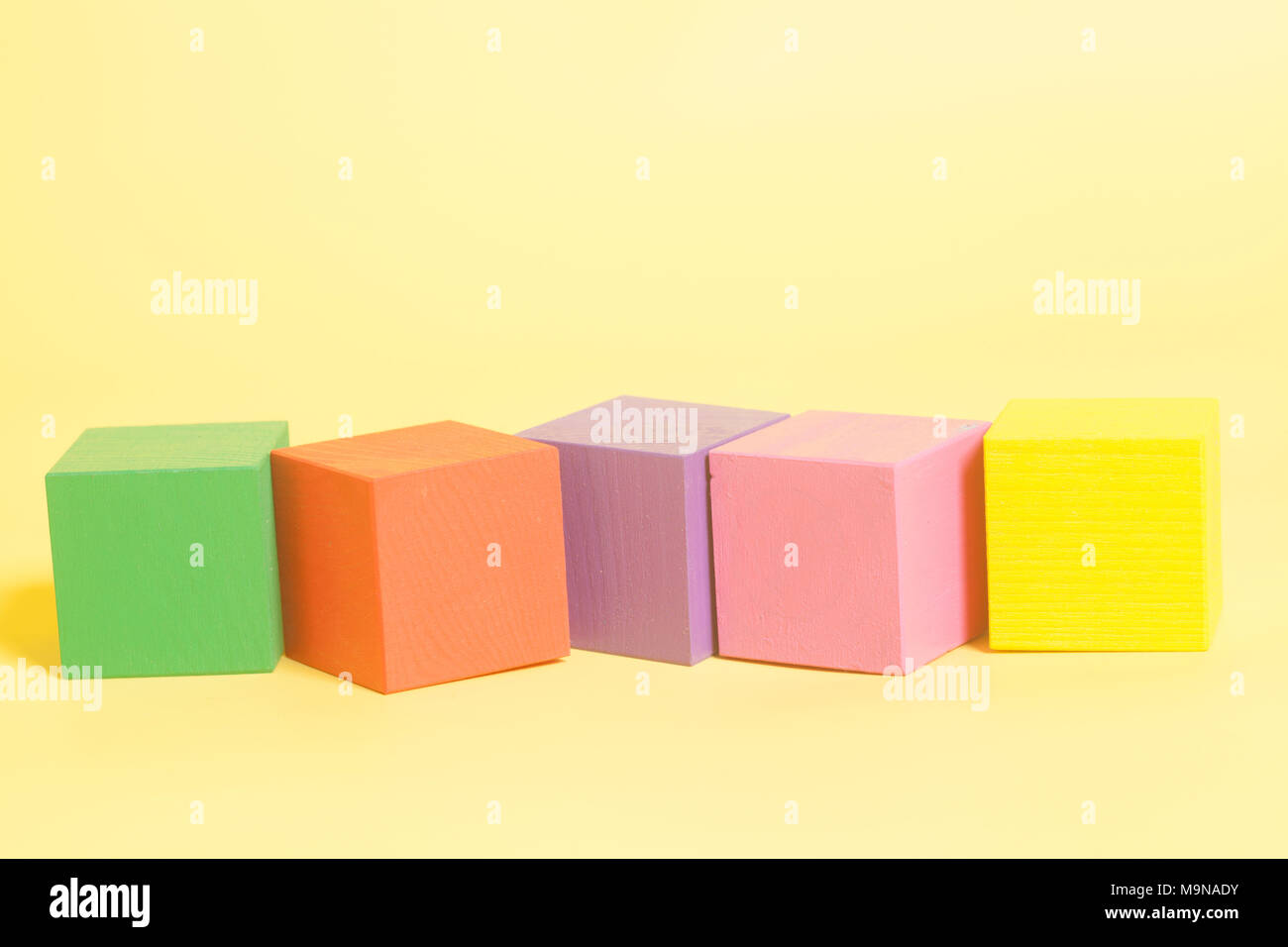 Coloured wooden cubes on a yellow background Stock Photo - Alamy