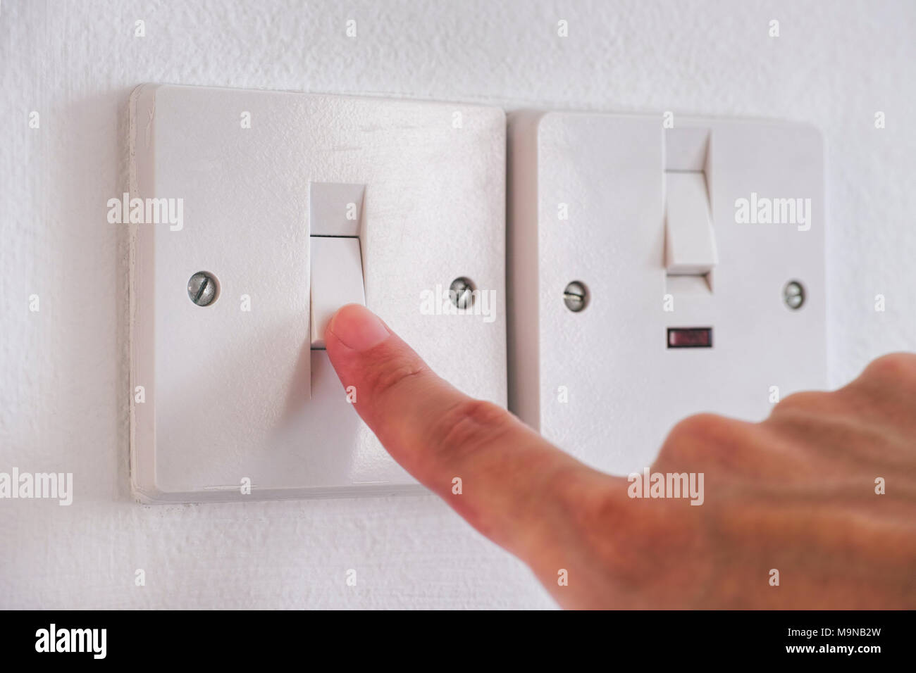 Person finger pushing light switch on white wall Stock Photo - Alamy