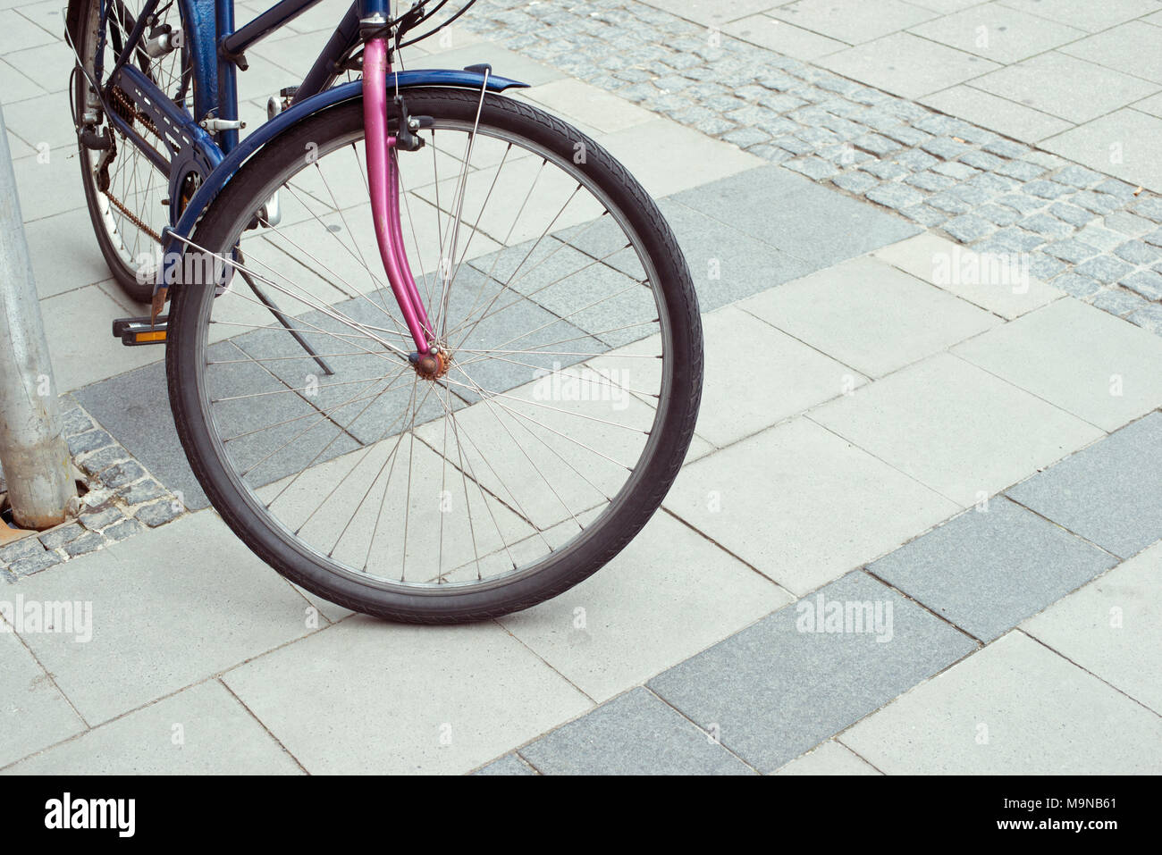 urban pavement background with focus on front wheel of vintage bicycle ...