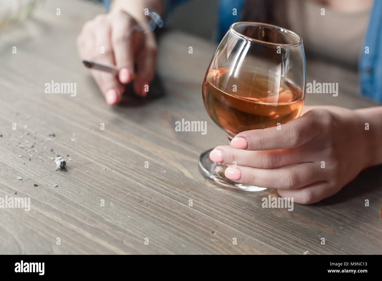 Young female alcoholic smoker social problems sitting at table smoking ...