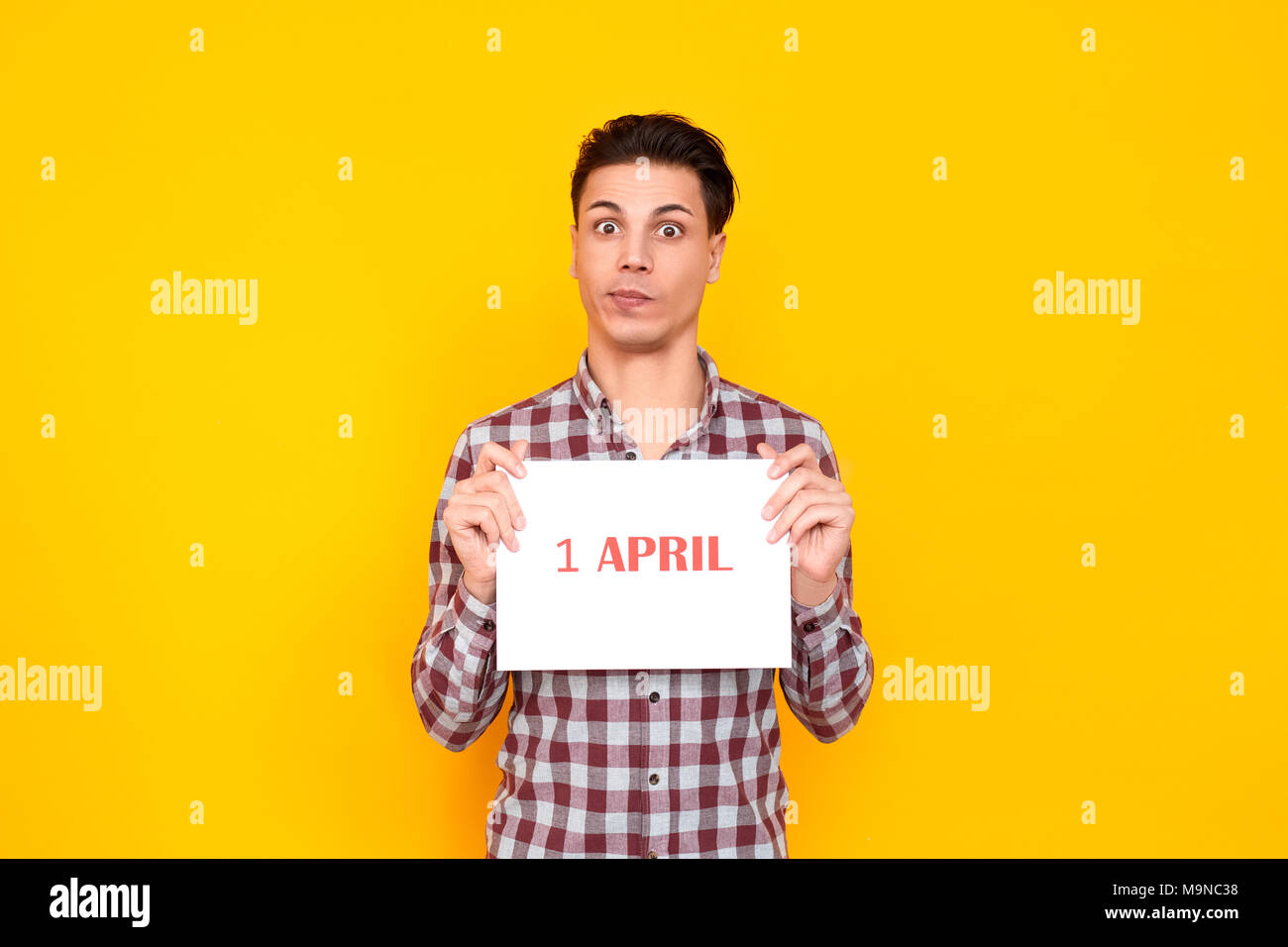 Shocked man holding white table with an inscription 1 april. Fool's day ...