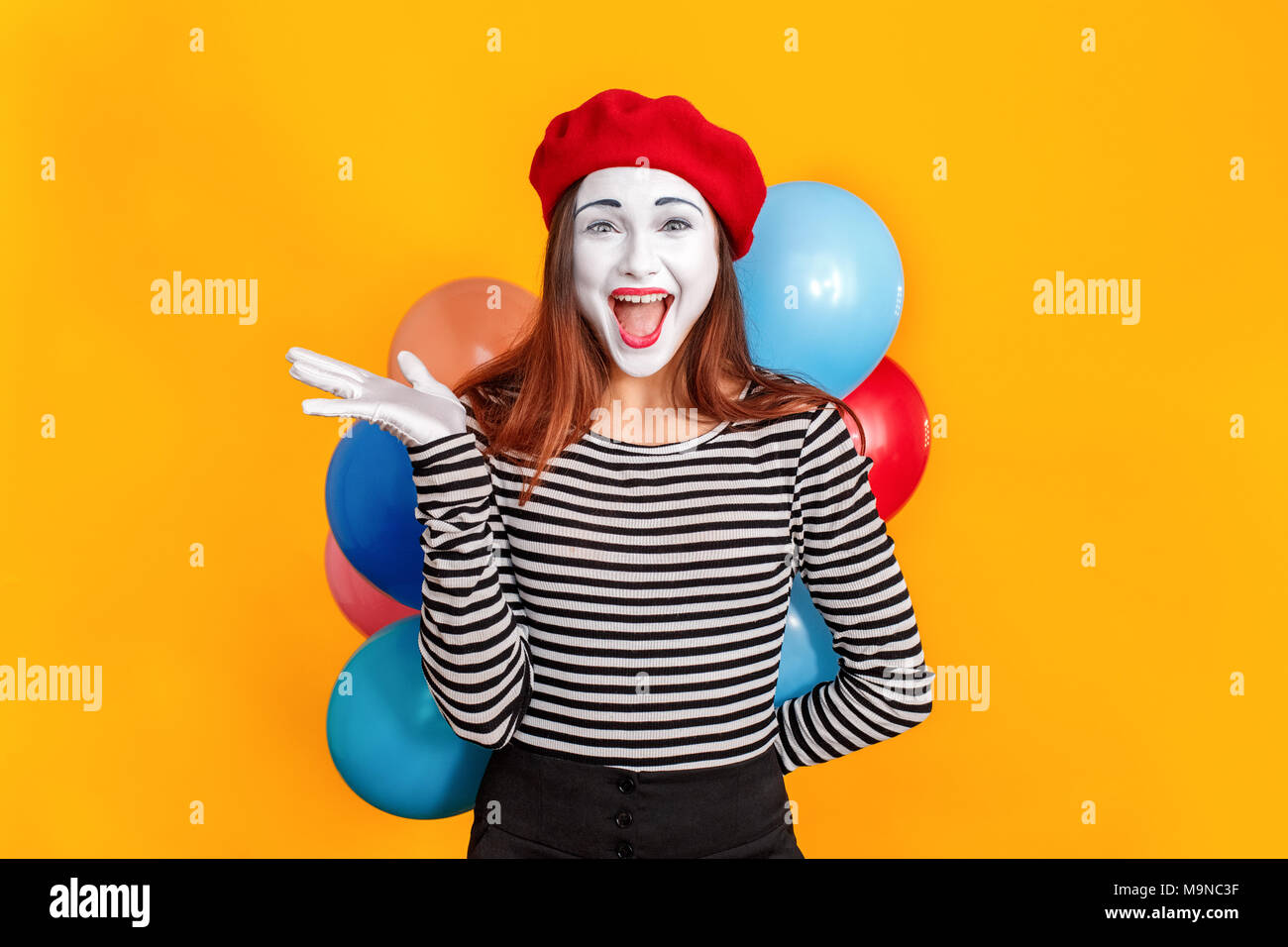 Surprise! Portrait of cute mime woman holding many colorful balloon ...