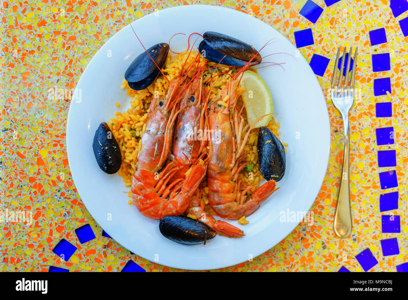 paella portion, rice with tiger shrimps, mussels and lemon Stock Photo ...