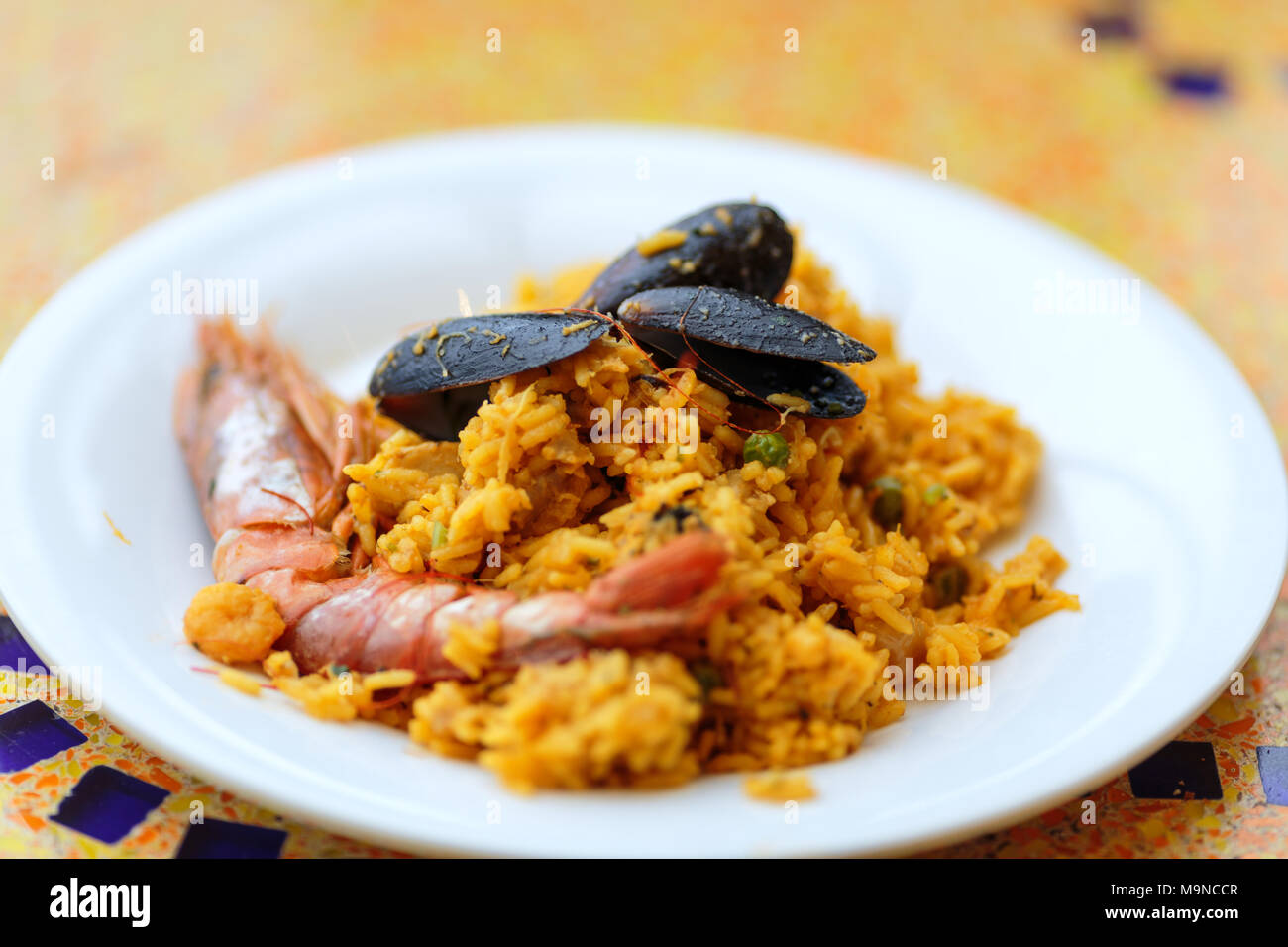 paella portion, rice with tiger shrimps, mussels and lemon Stock Photo ...