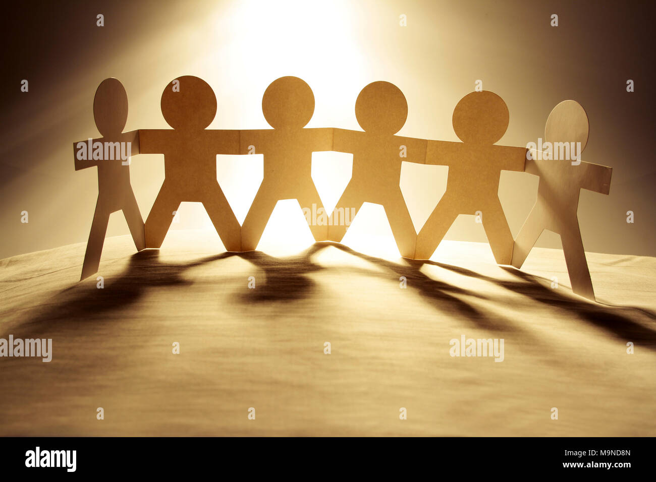 Team of paper chain people in a row holding hands Stock Photo - Alamy