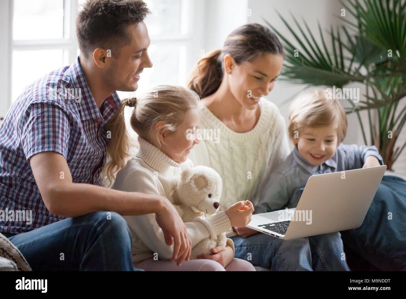 Young family with adopted children using laptop together at home ...