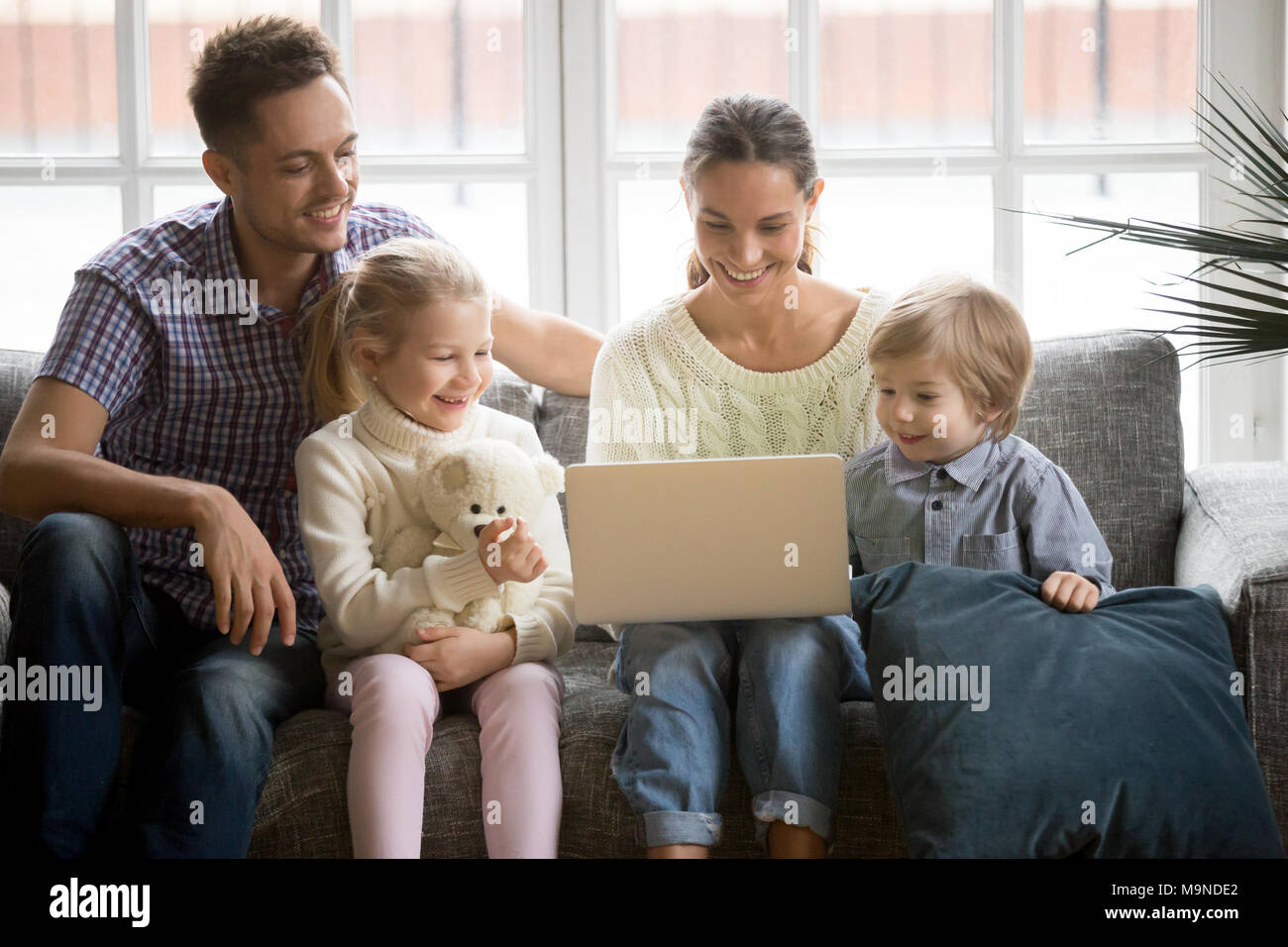 Happy family with adopted children have fun using laptop sitting on ...