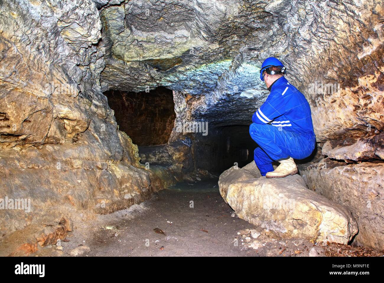 Miner man underground in a mine tunnel. Worker in overalls, safety ...