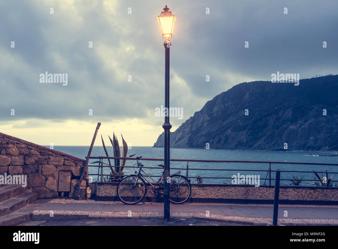 Street lamp lantern turned on at evening time illuminating a path with ...