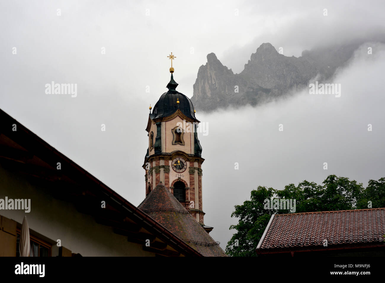 On an overcast, rainy summer day, the peaks of the Zugspitze German ...